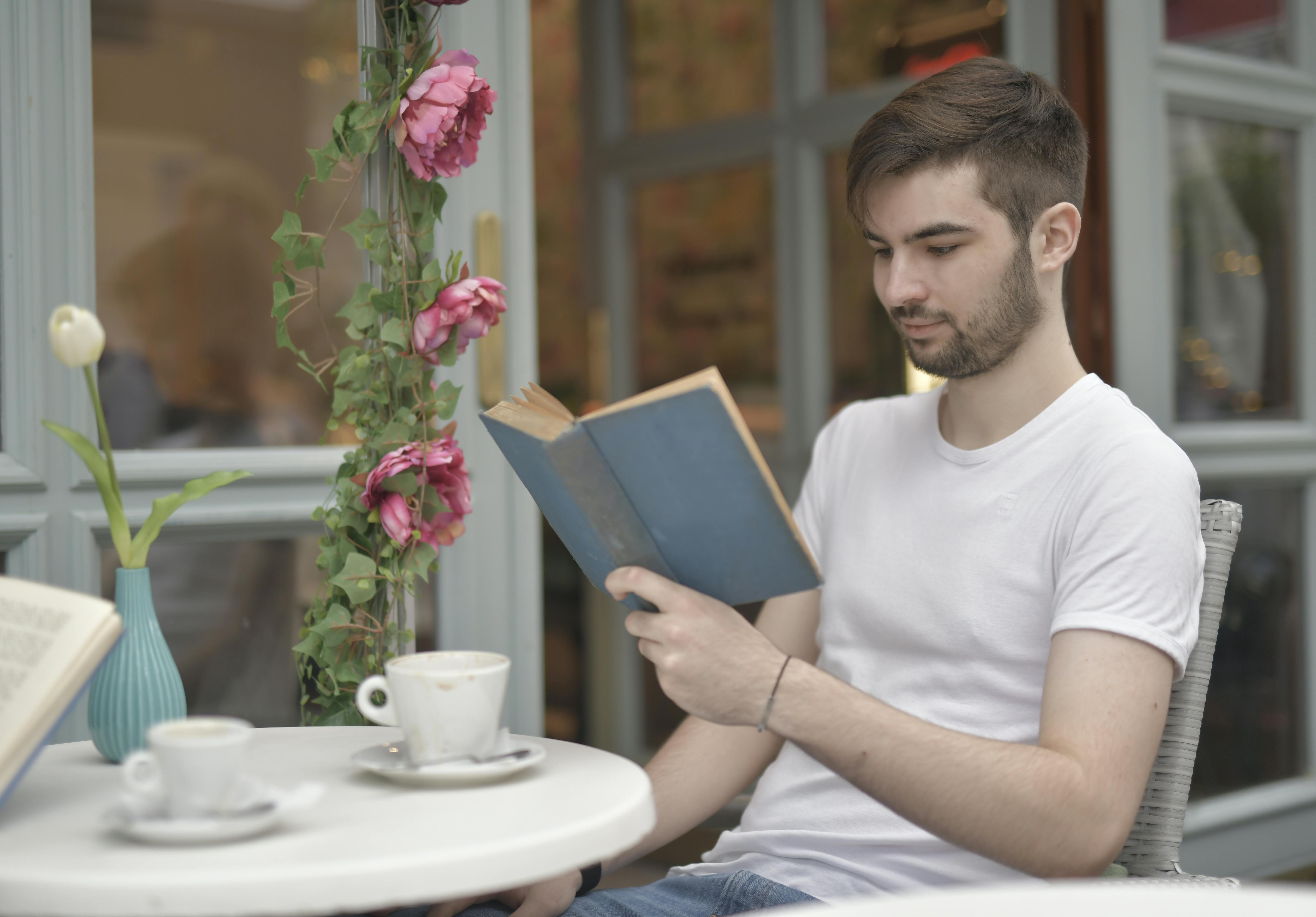 Man in White Crew Neck T-shirt Reading Book · Free Stock Photo