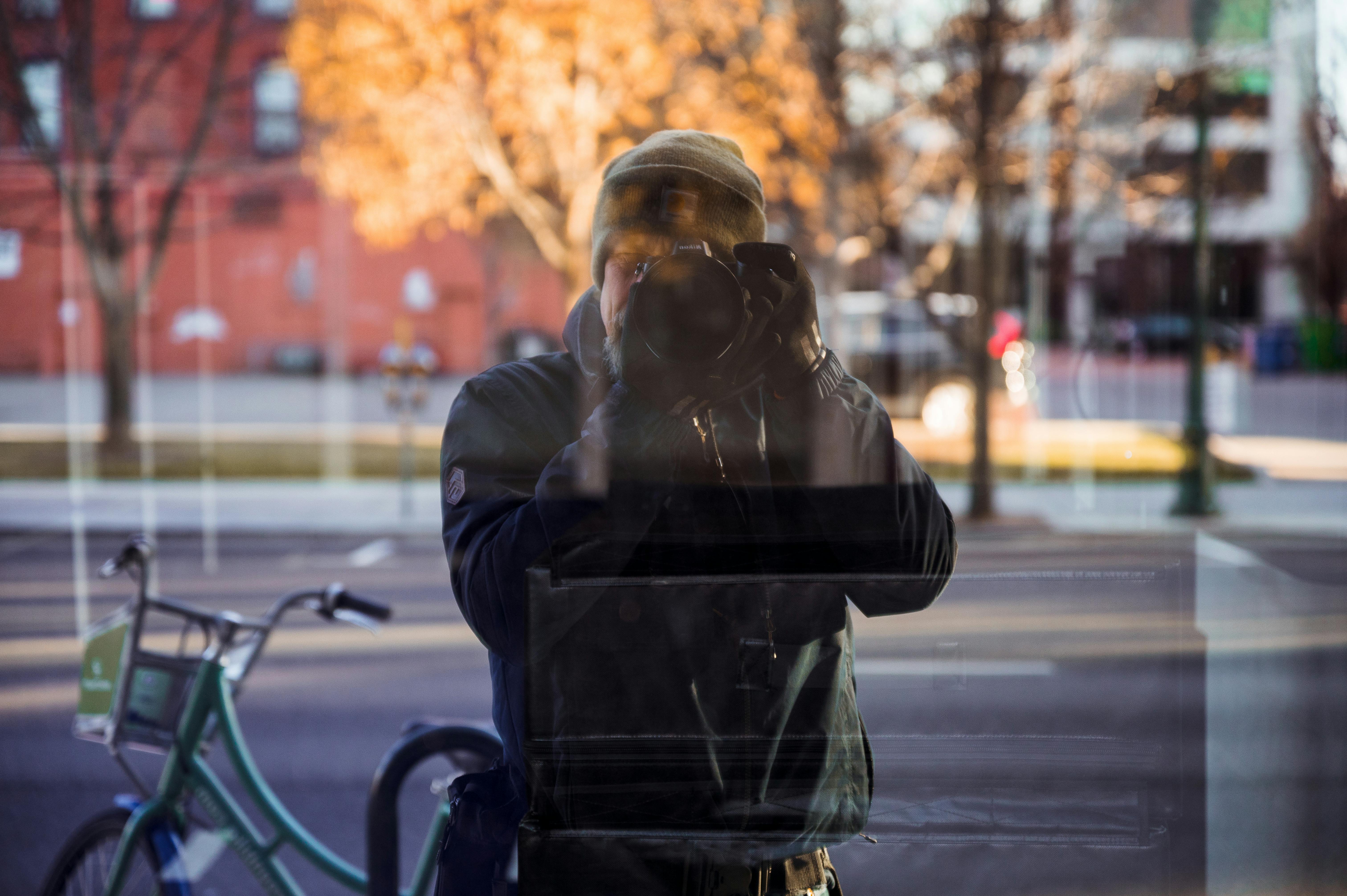 Man Taking Photo Through Glass Window · Free Stock Photo