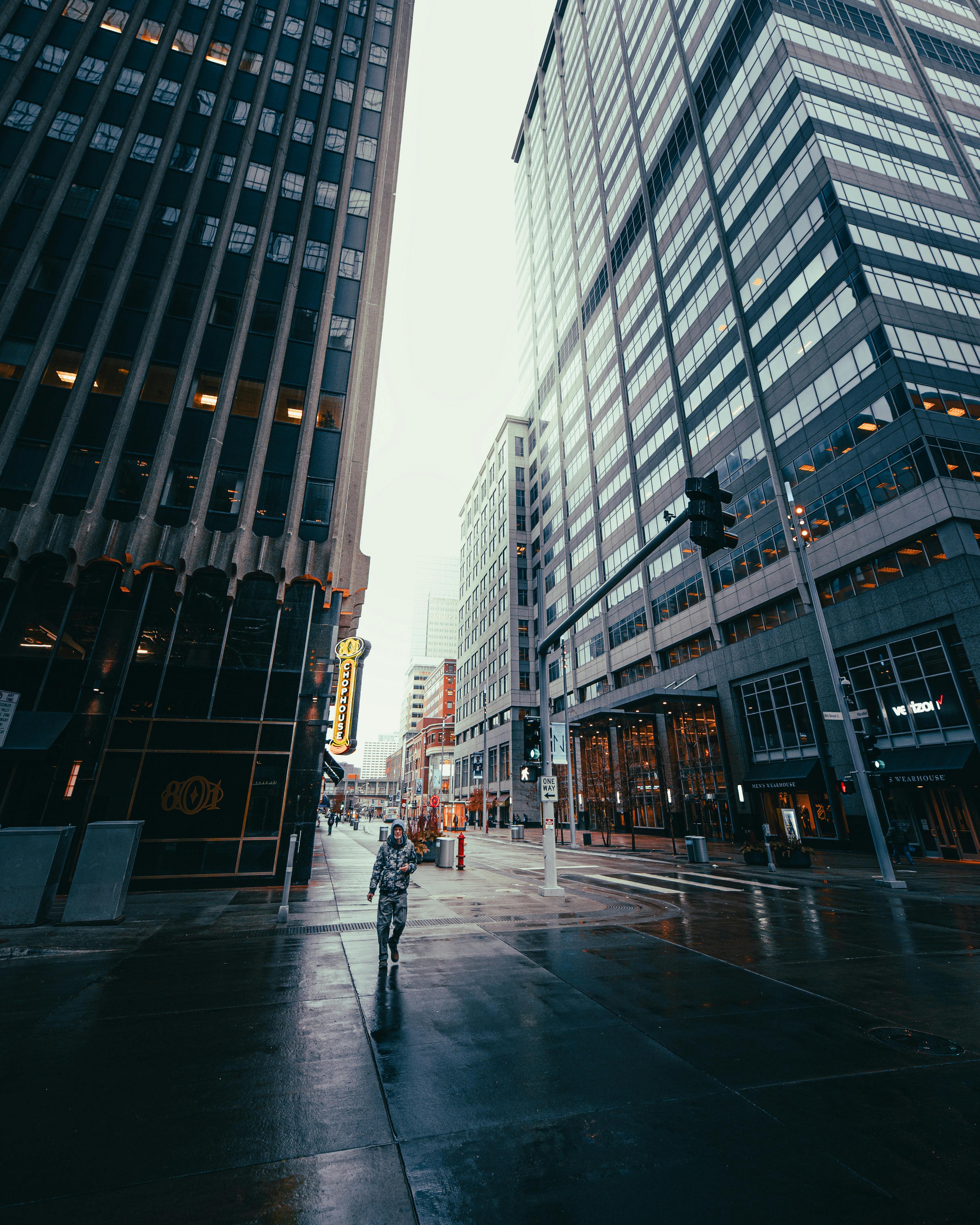 Man Walking on Sidewalk Near High Rise Buildings · Free Stock Photo