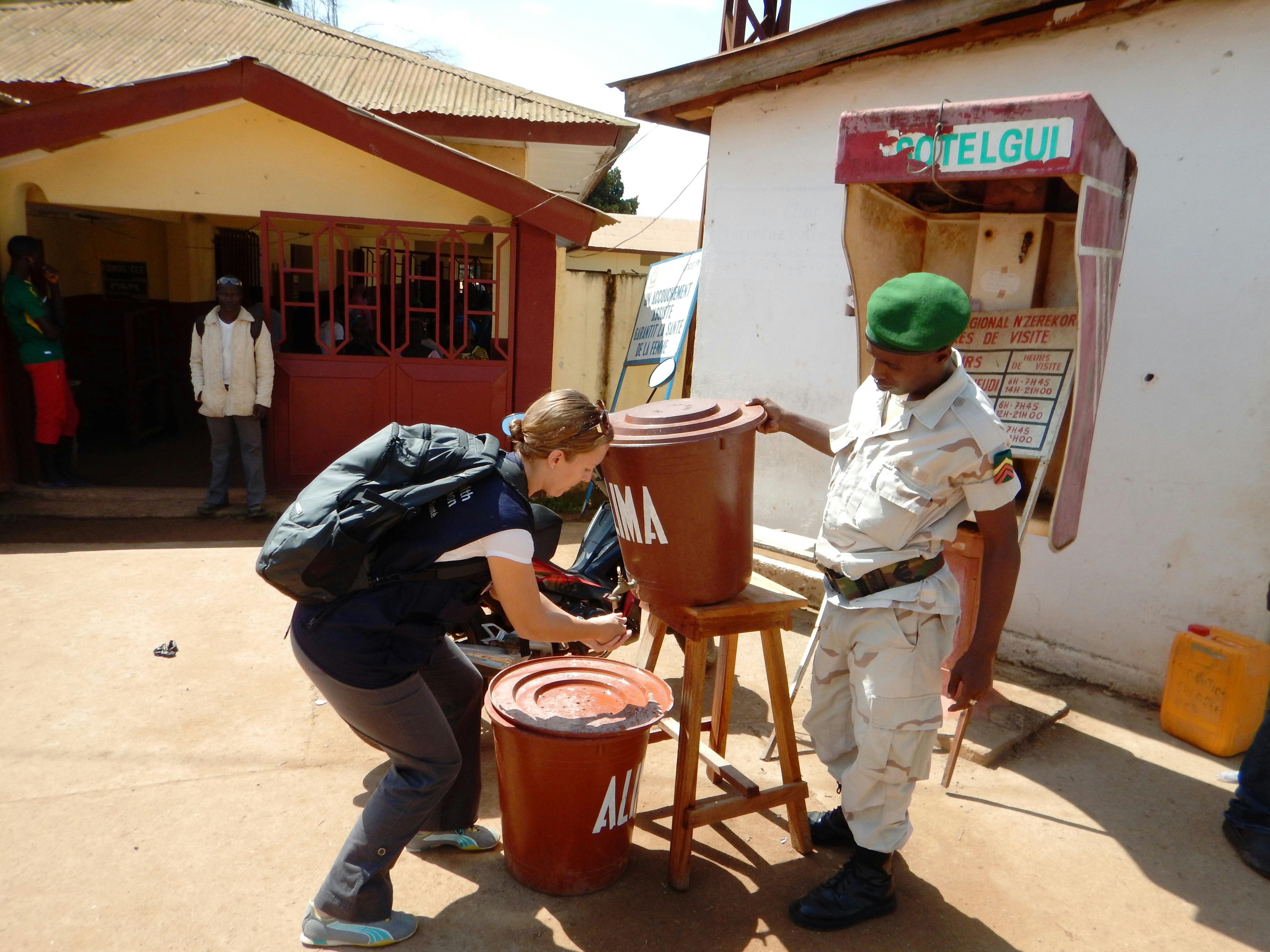 Tourist washing hands from bucket near black service man outdoors ...