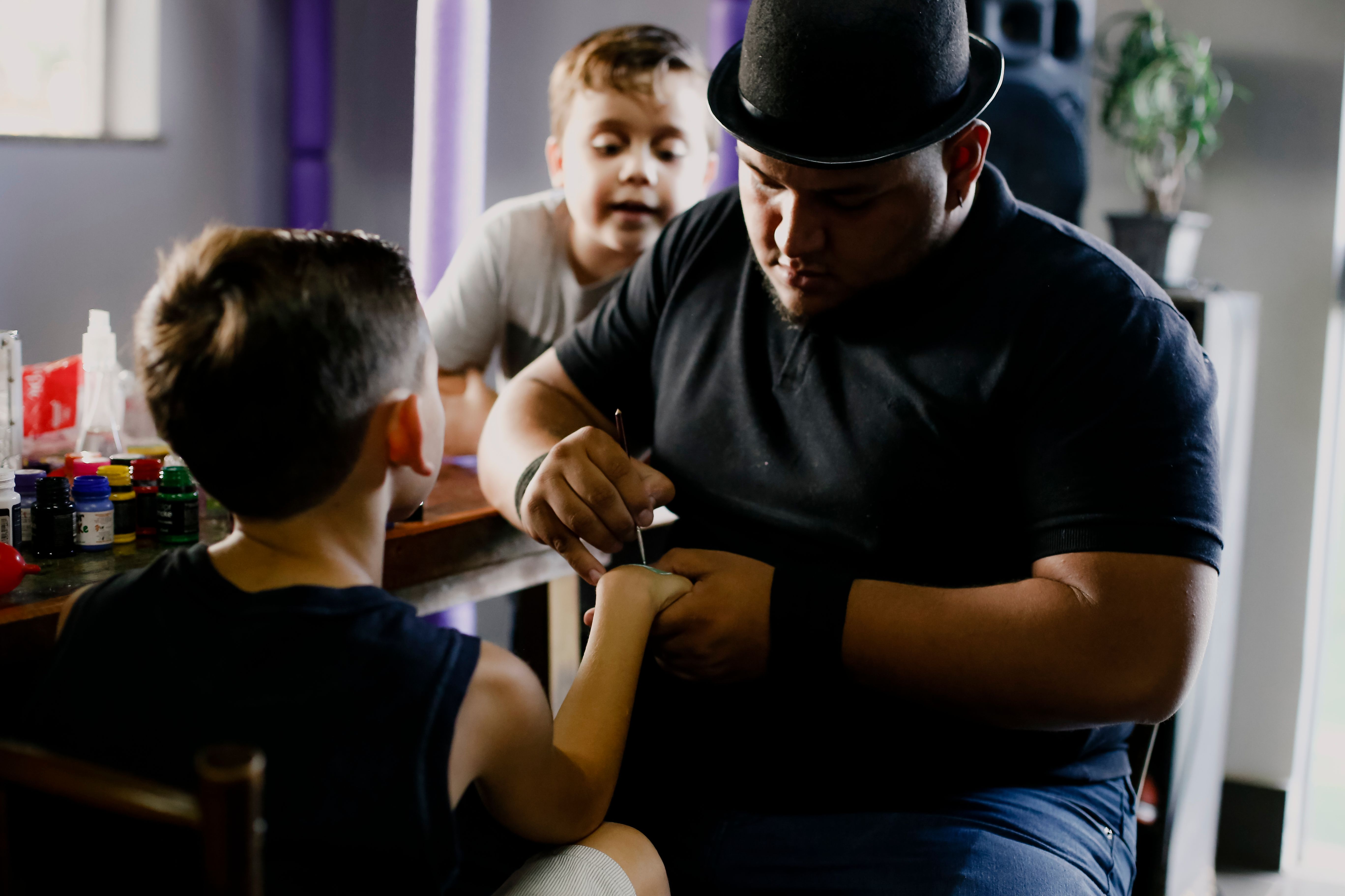 Male artist painting on hand of boy in art studio · Free Stock Photo