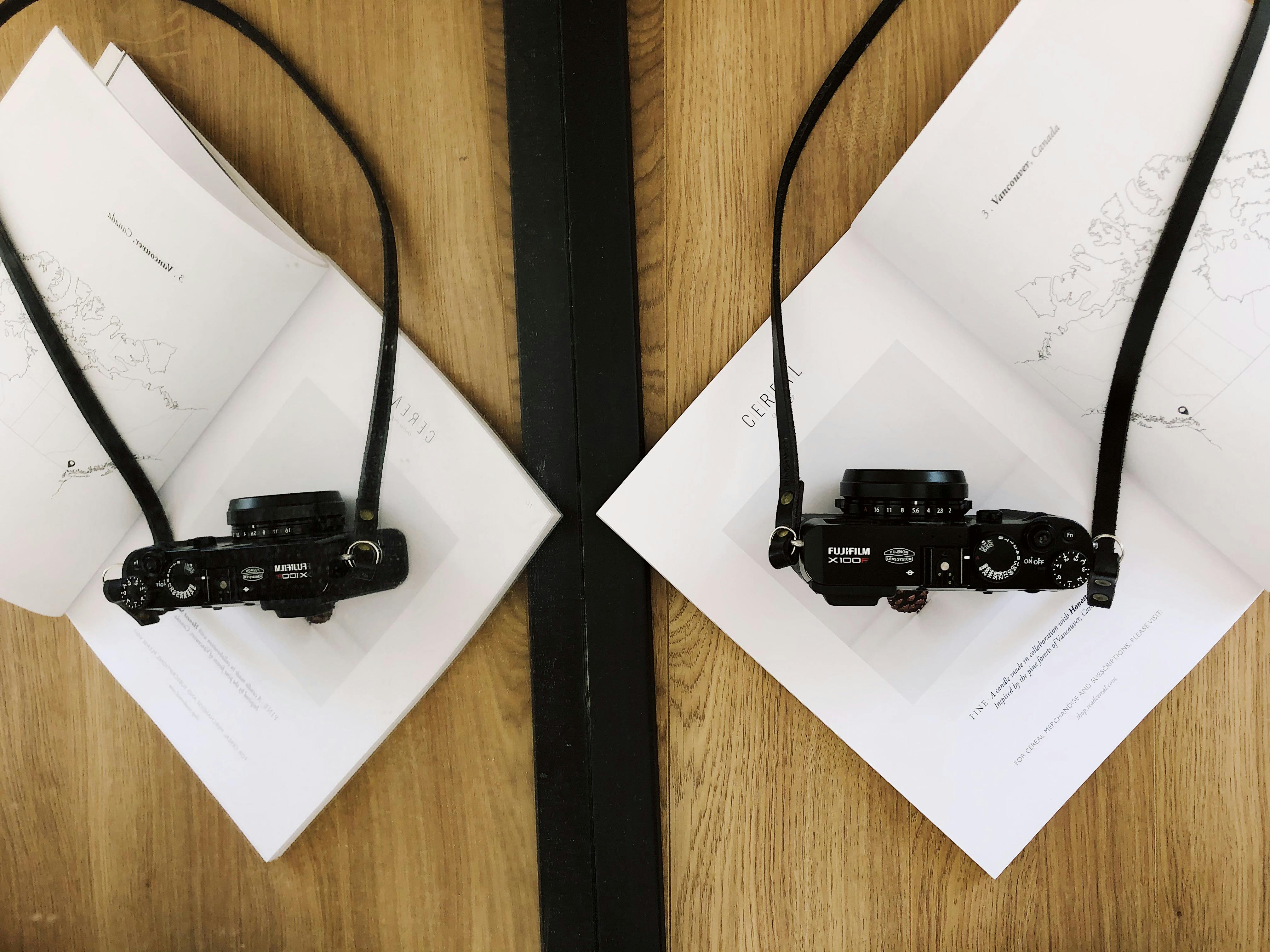 Photo camera placed on book near mirror on wooden table · Free Stock Photo