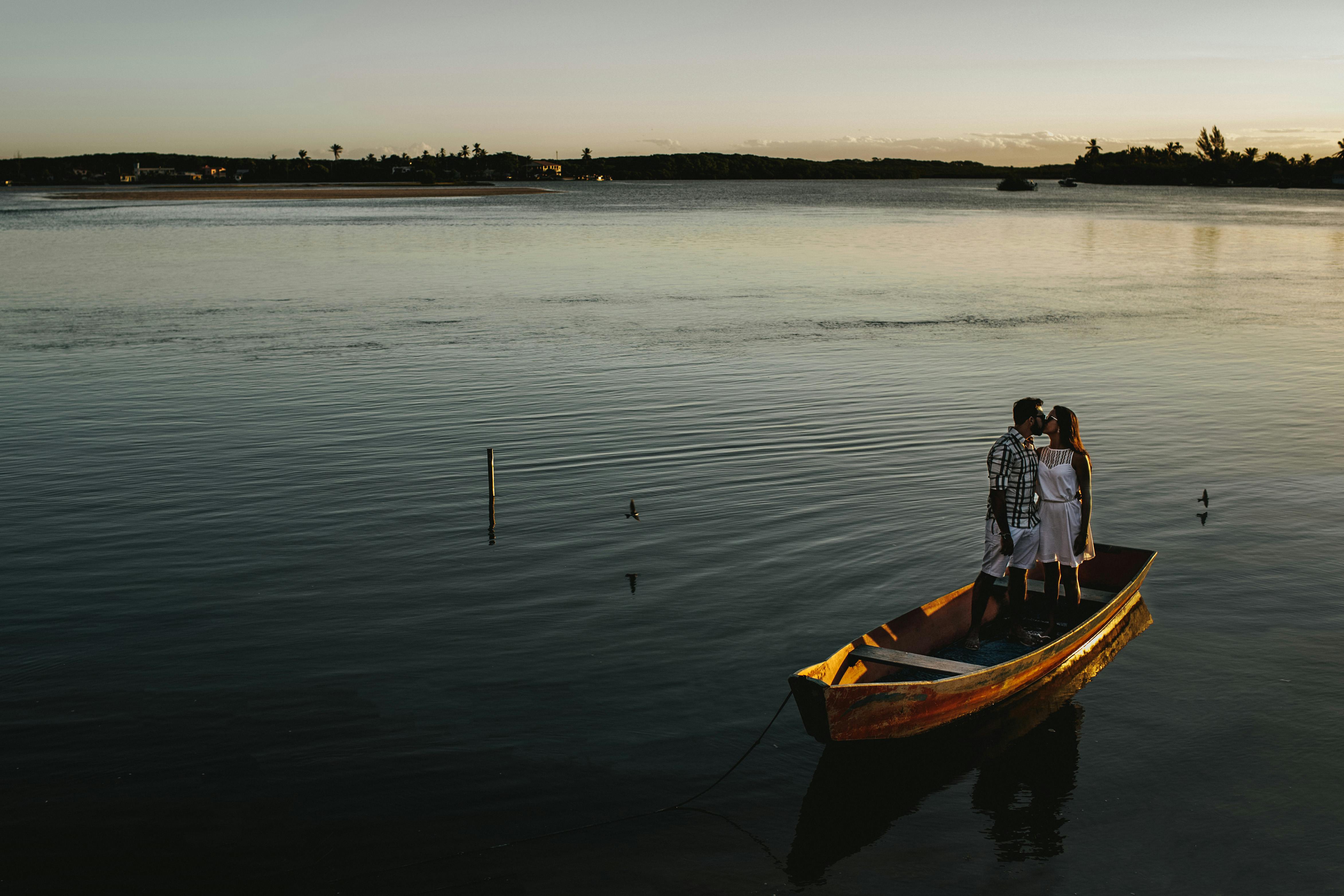 Anonymous young couple kissing in wooden boat · Free Stock Photo
