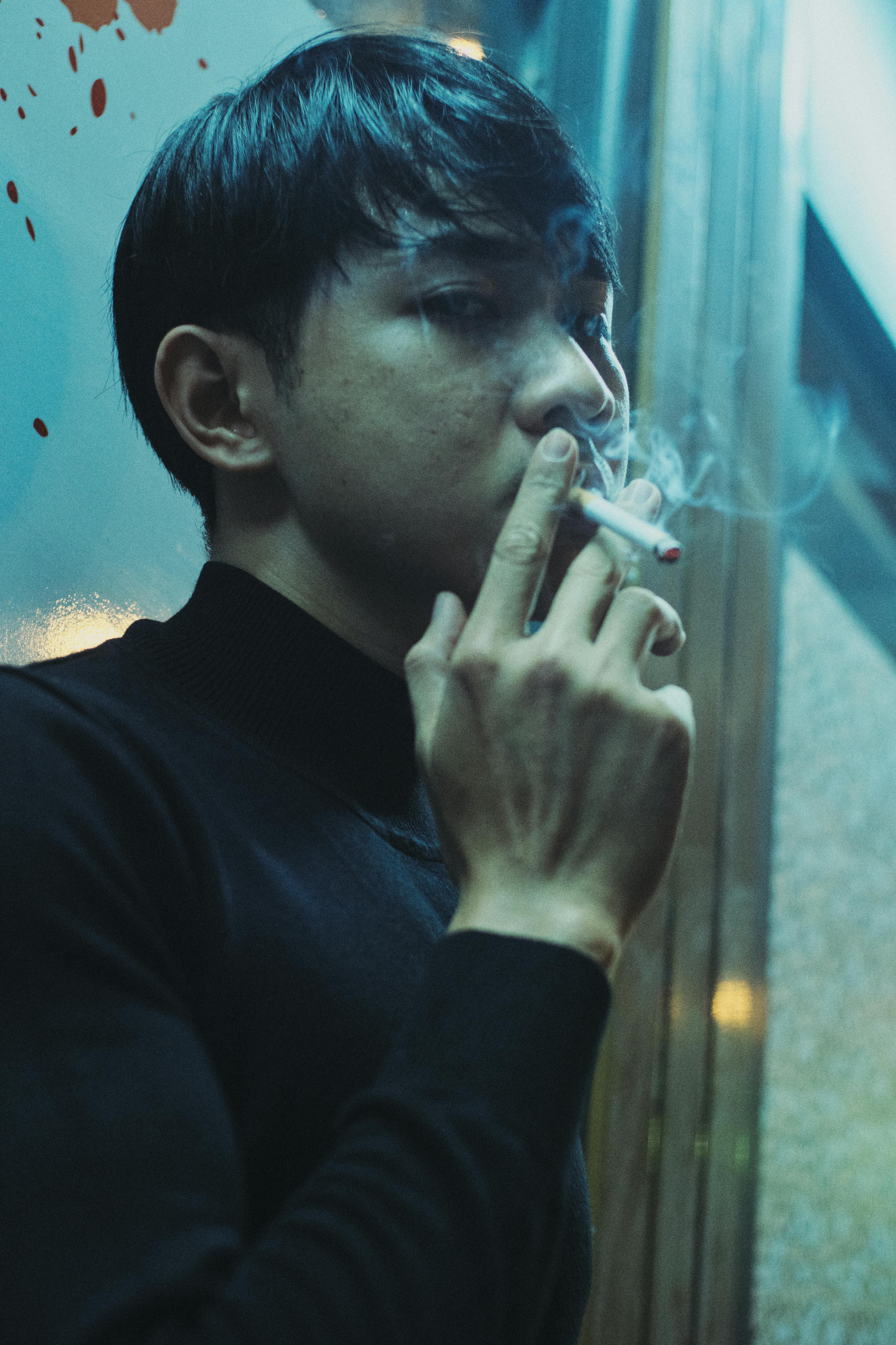 Calm ethnic guy exhaling smoke from cigarette · Free Stock Photo