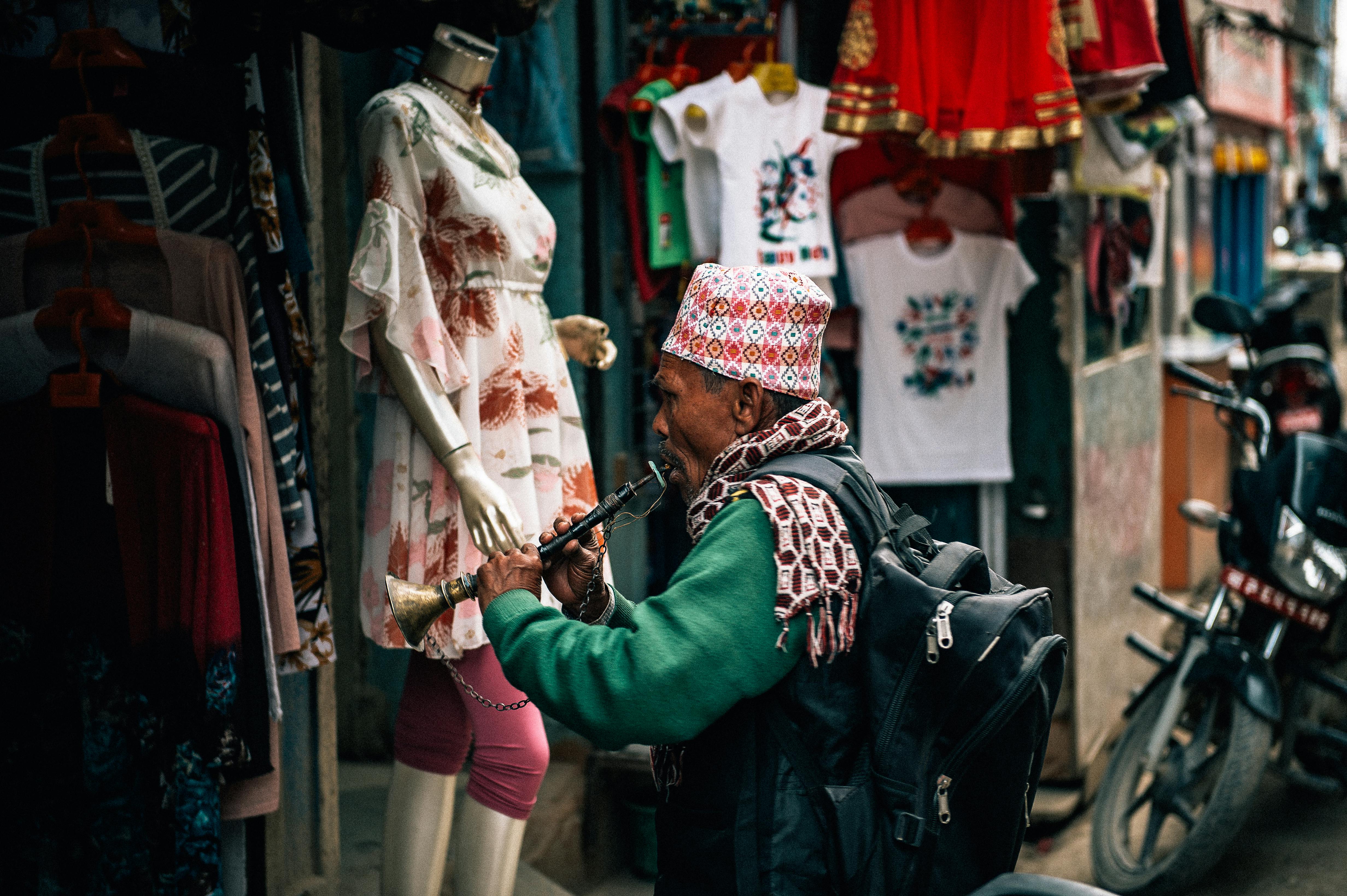 Ethnic musician playing pipe near clothing store on street · Free Stock ...