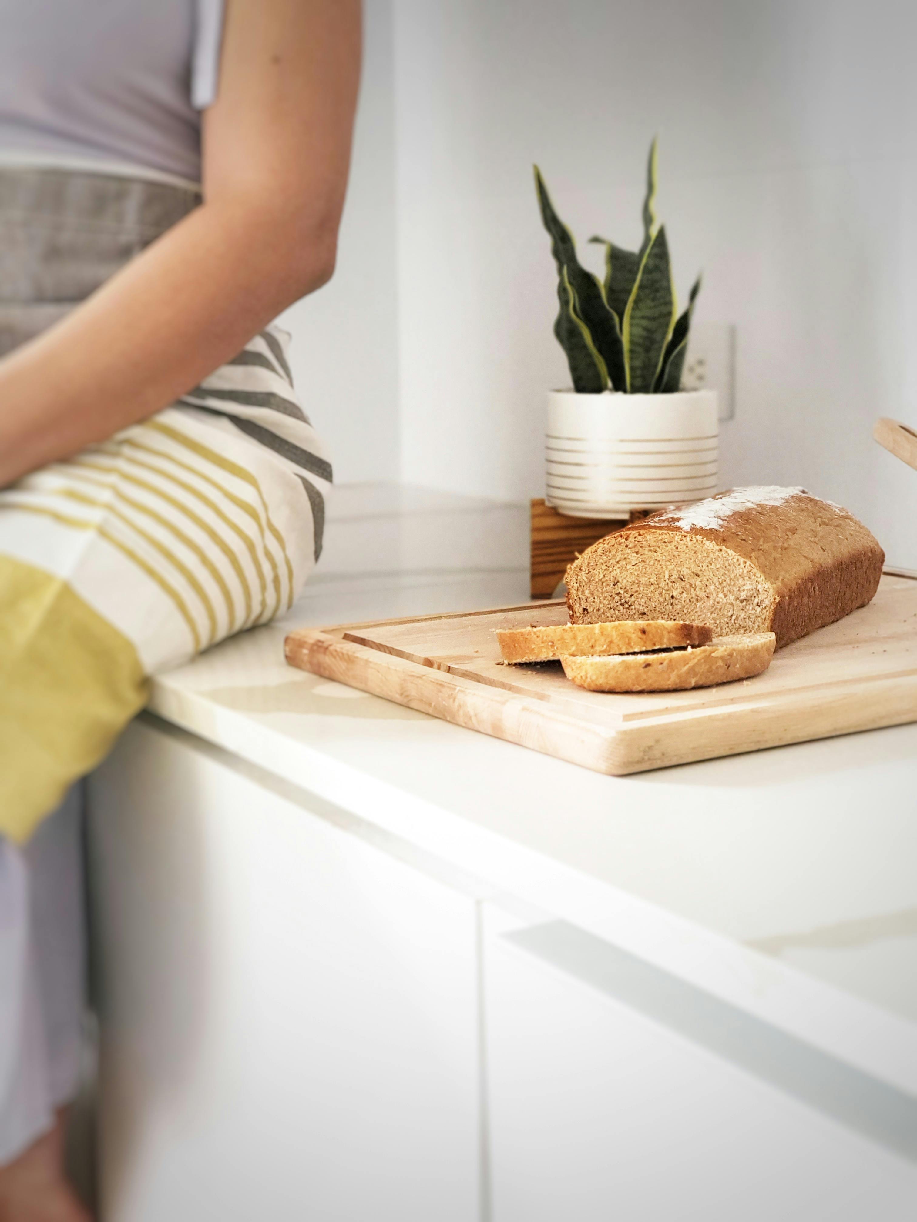Photo of a Person Sitting Near a Loaf of Bread · Free Stock Photo