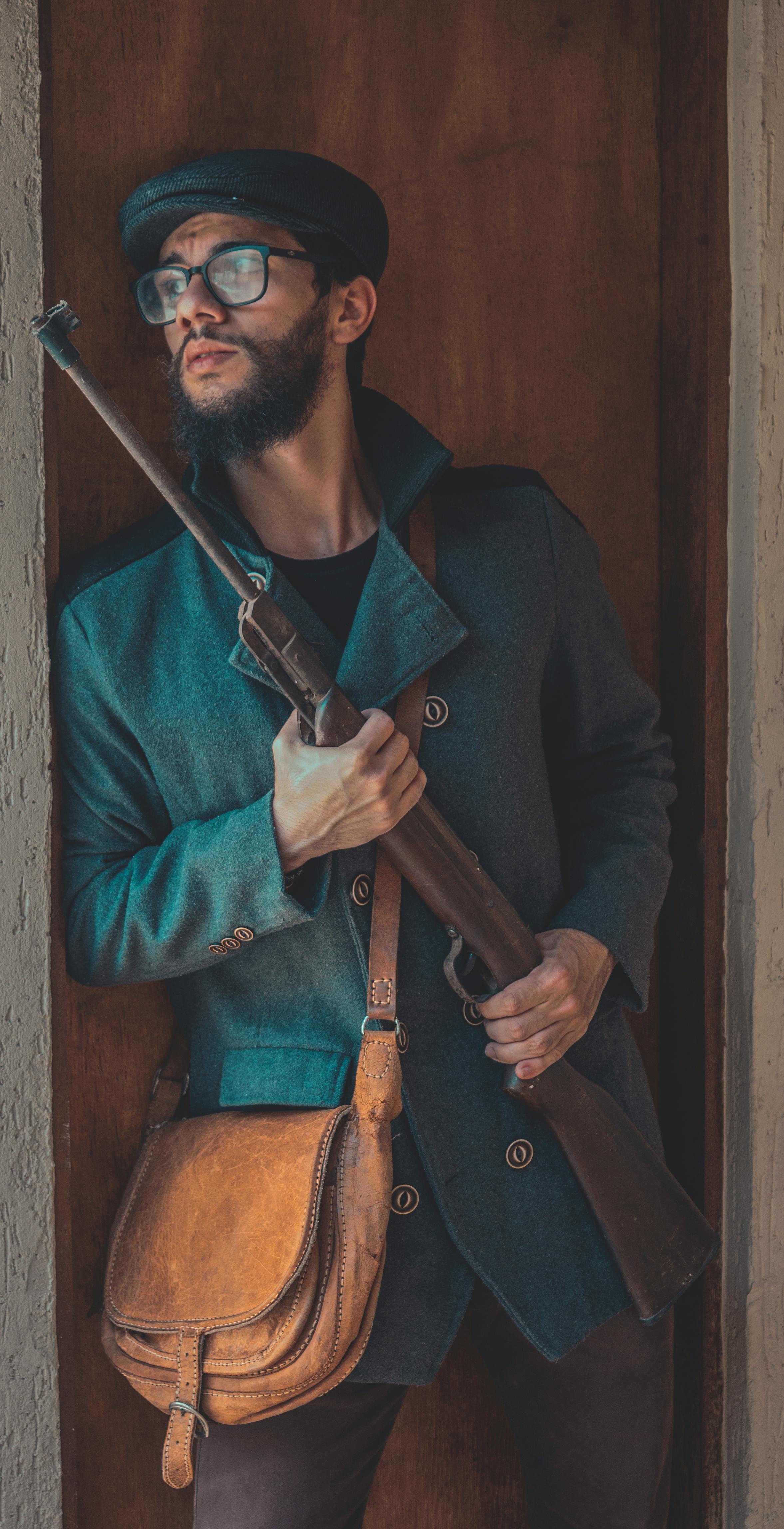Photo of a Man with Eyeglasses Holding a Rifle · Free Stock Photo