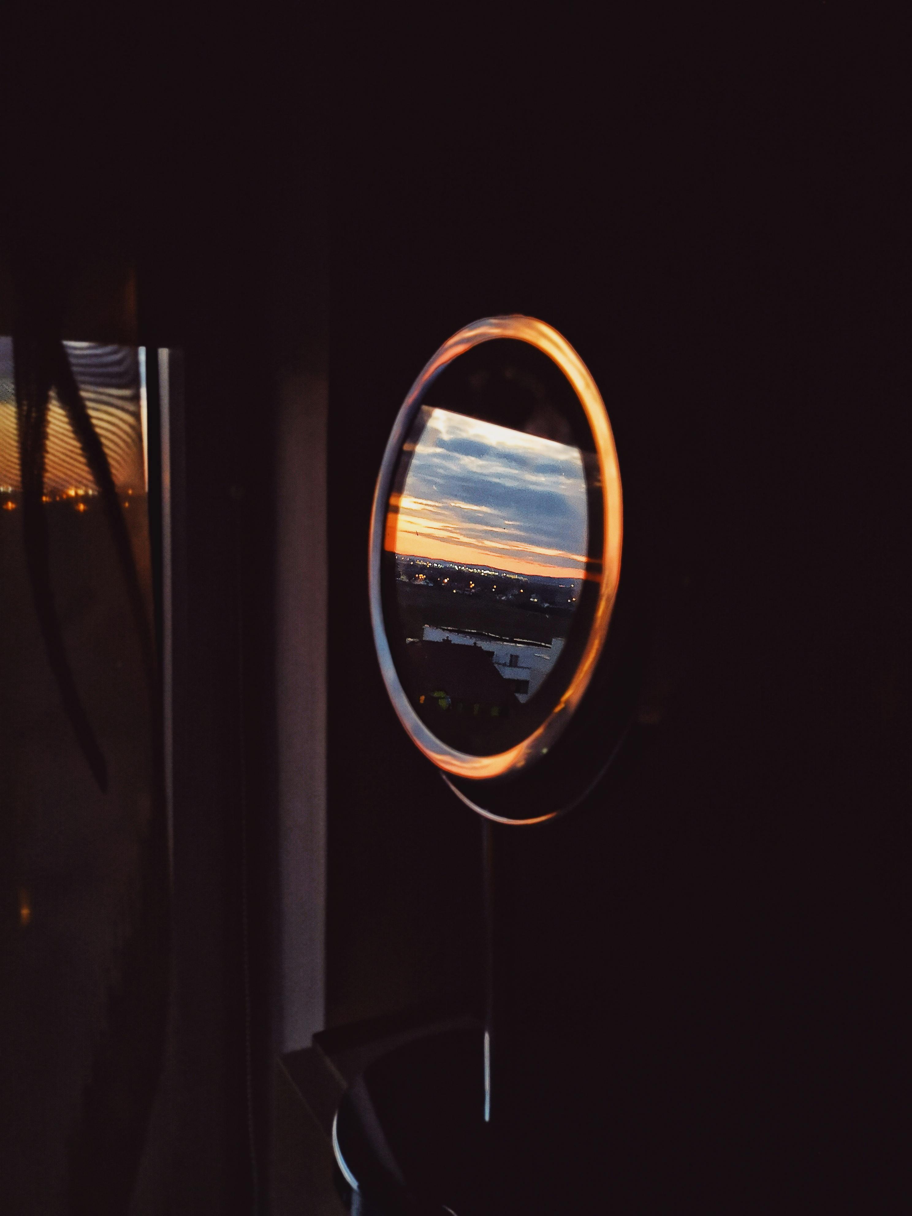 Illuminated round mirror reflecting sunset sky · Free Stock Photo