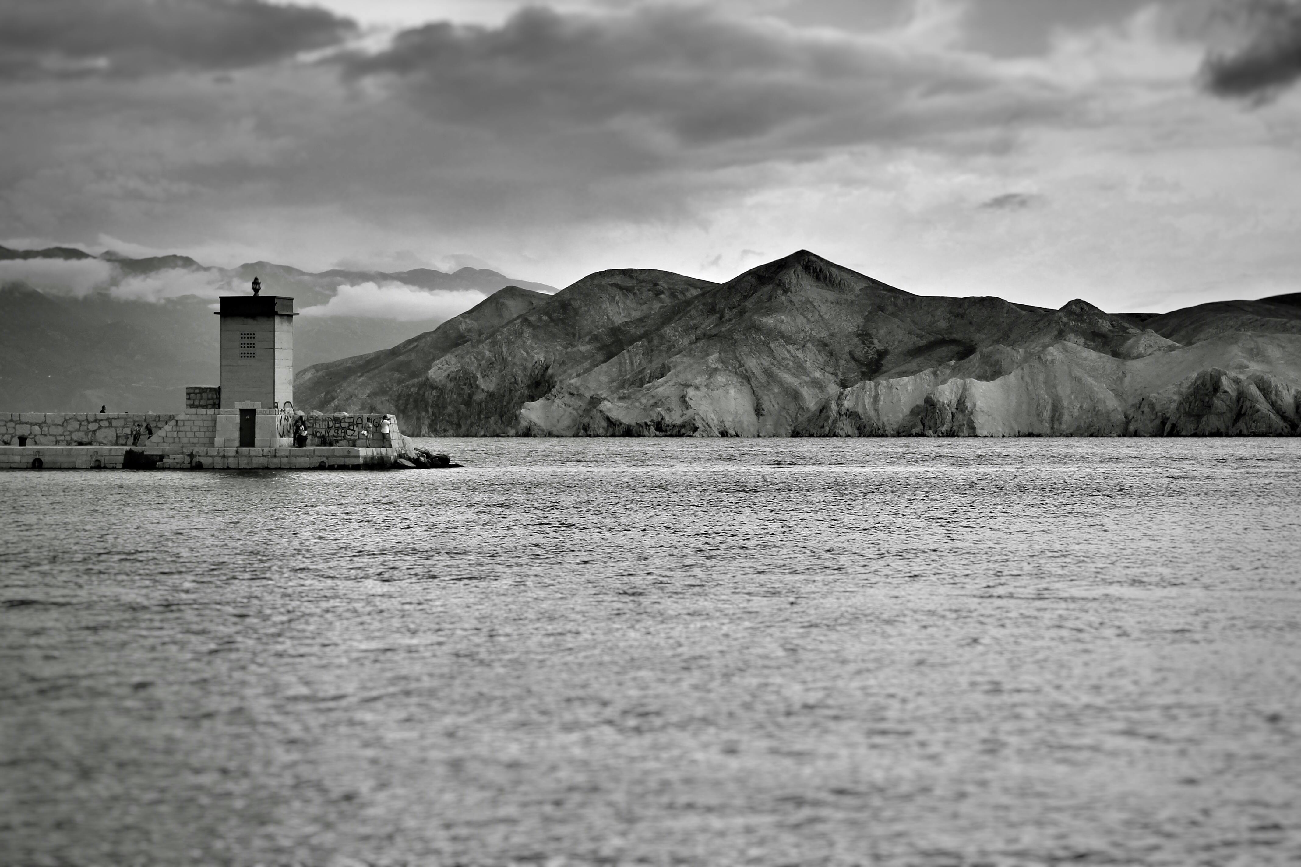 Lonely lighthouse on seashore near highland against overcast sky · Free ...