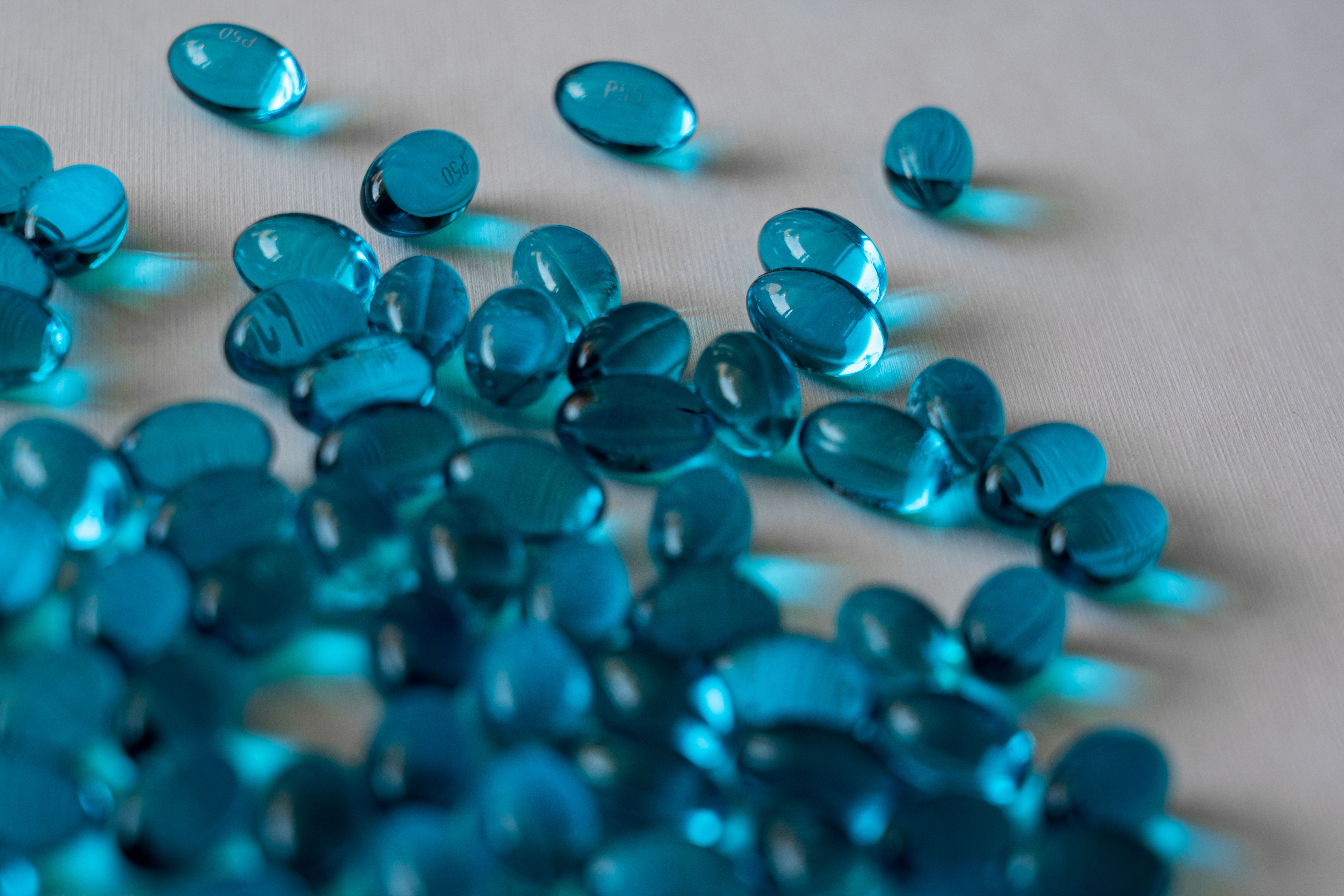 Blue Gel Capsules on White Textile · Free Stock Photo