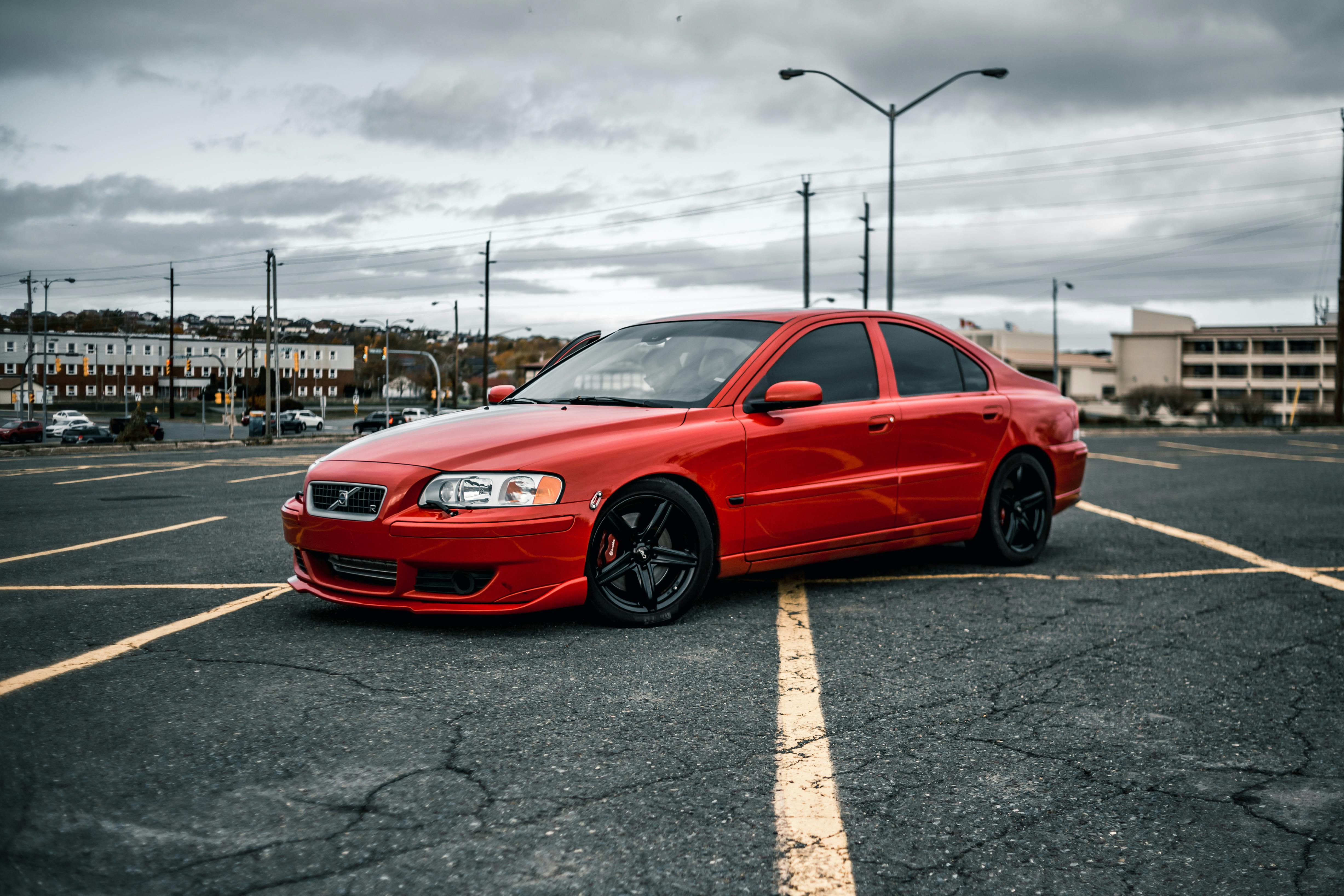 Modern red car on asphalt road in city under sky · Free Stock Photo
