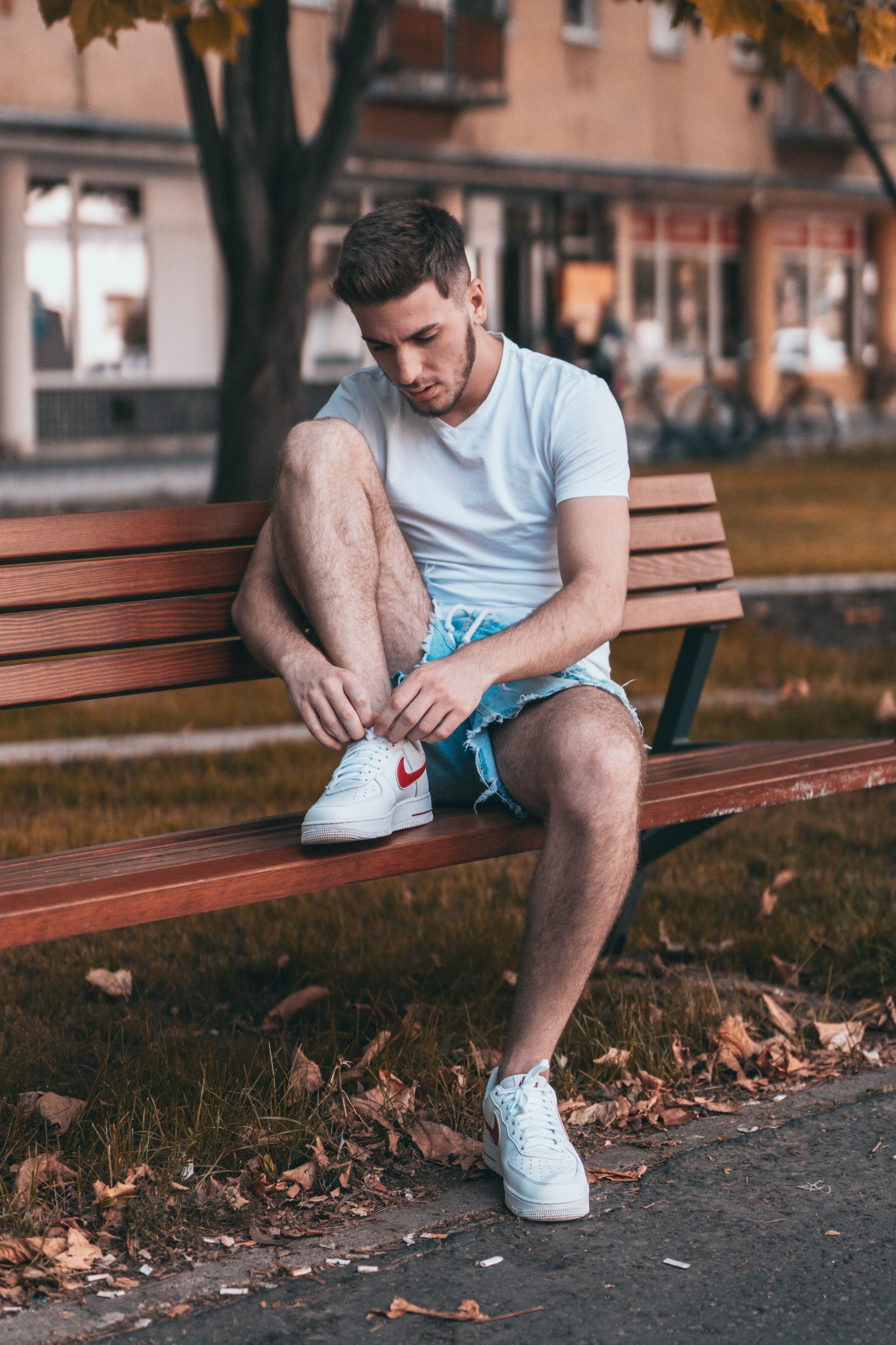 Man in White Crew Neck T-shirt Sitting on Brown Wooden Bench · Free ...