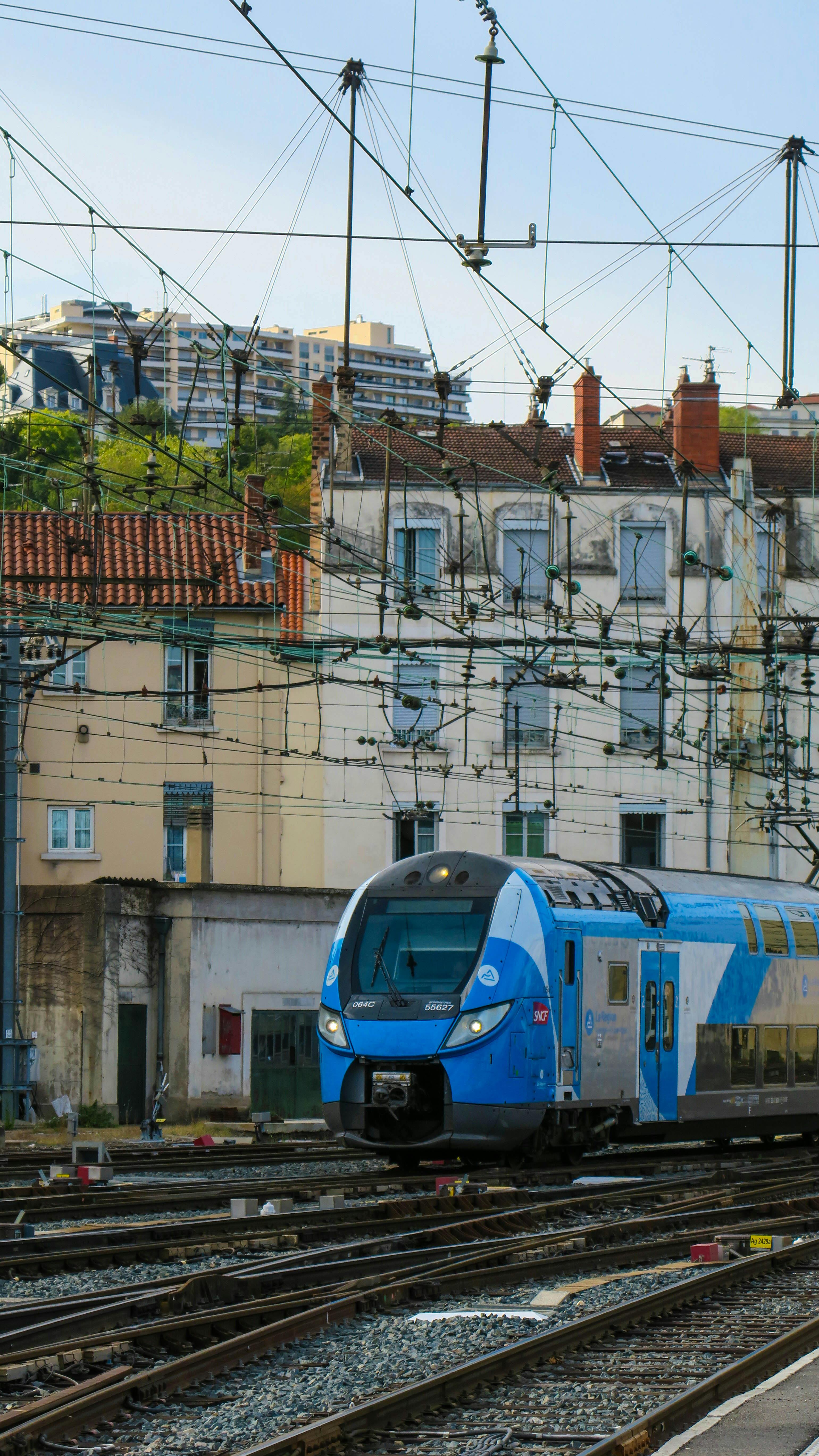 Blue Train in Front of Beige Concrete Building · Free Stock Photo