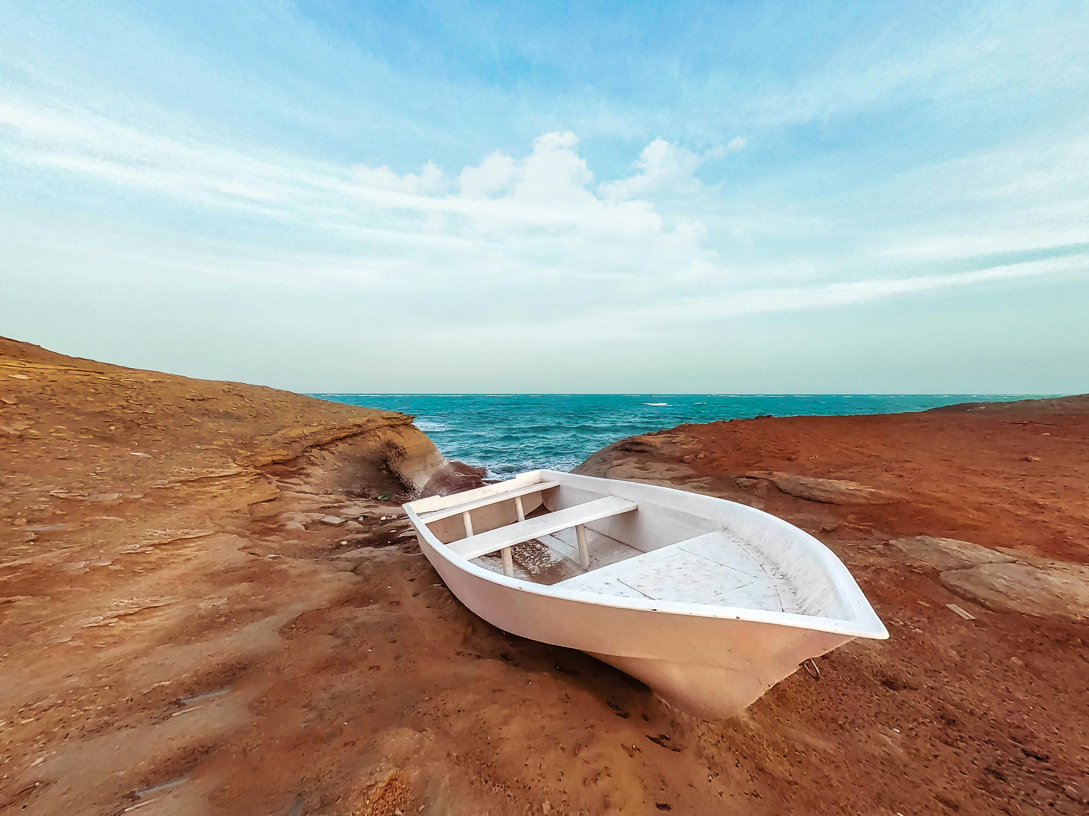White Boat on Brown Sand Near Body of Water · Free Stock Photo