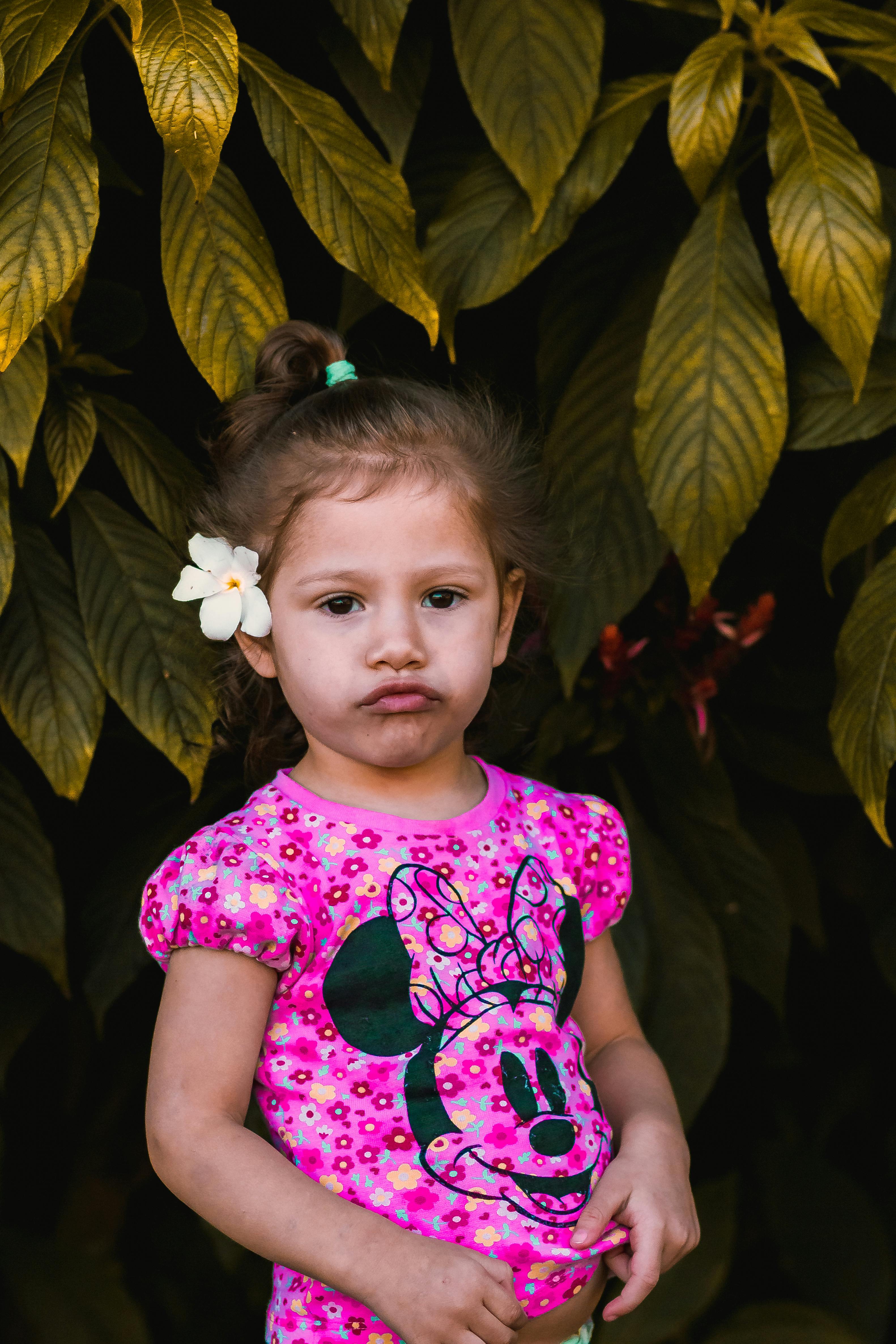 Girl with puffy cheeks in bright wear standing near shrub · Free Stock ...
