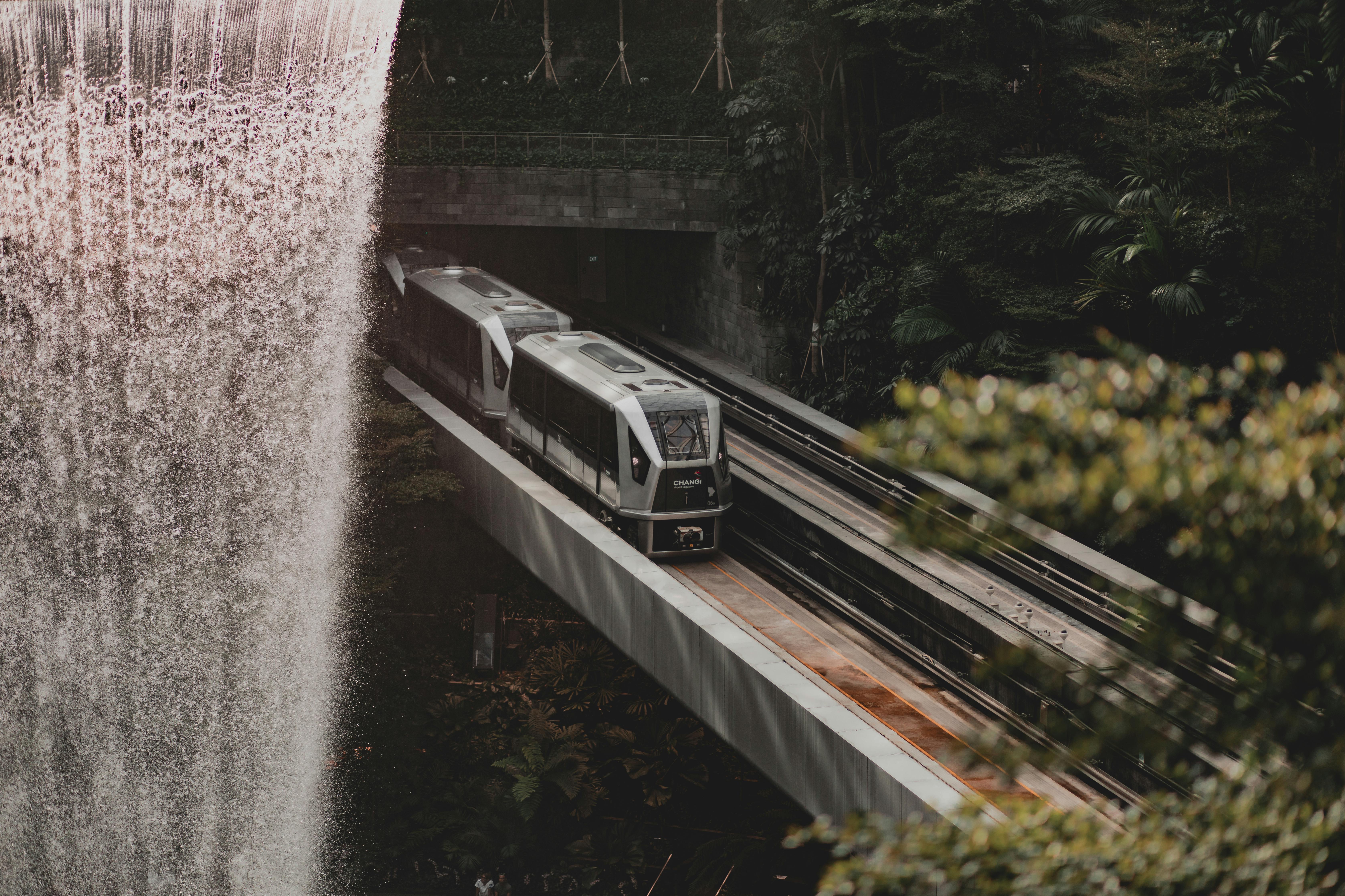 Scenery of modern train riding under waterfall bridge · Free Stock Photo