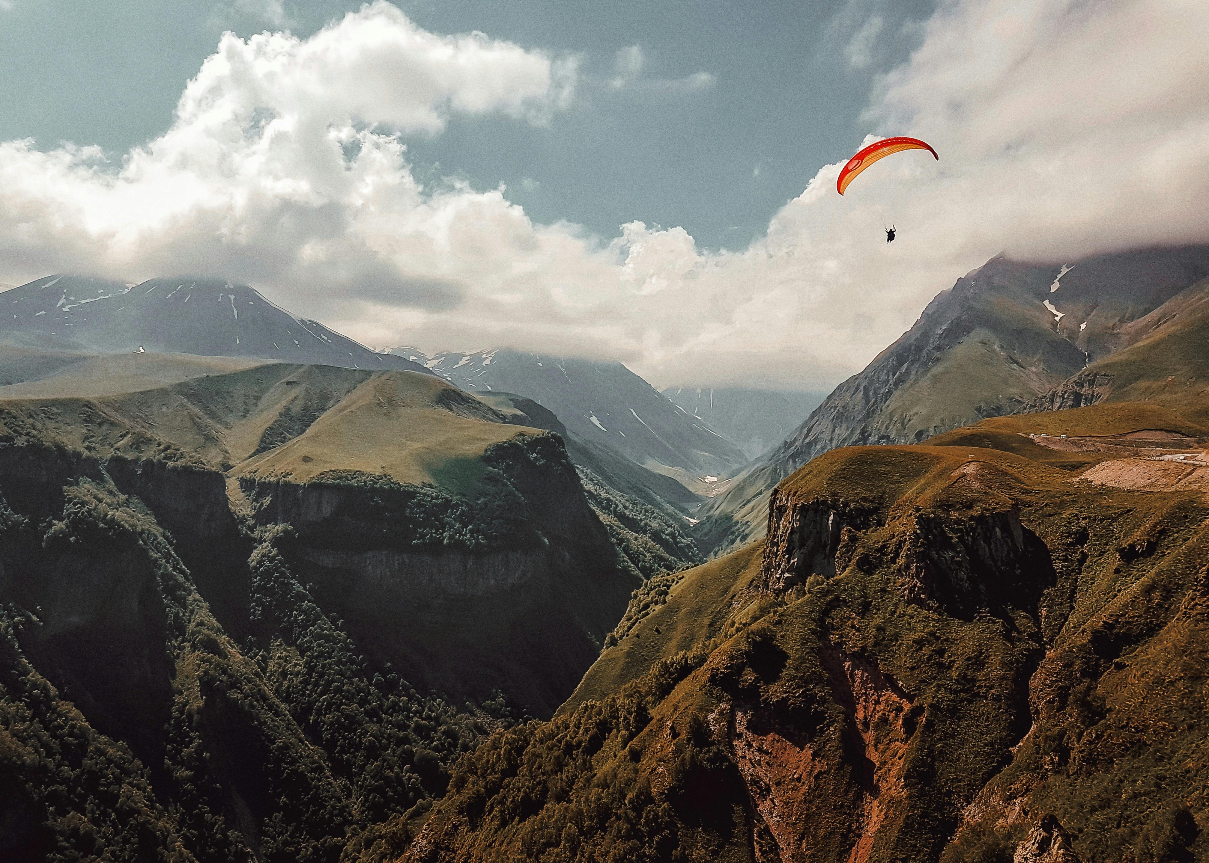 Person Paragliding over Mountains · Free Stock Photo