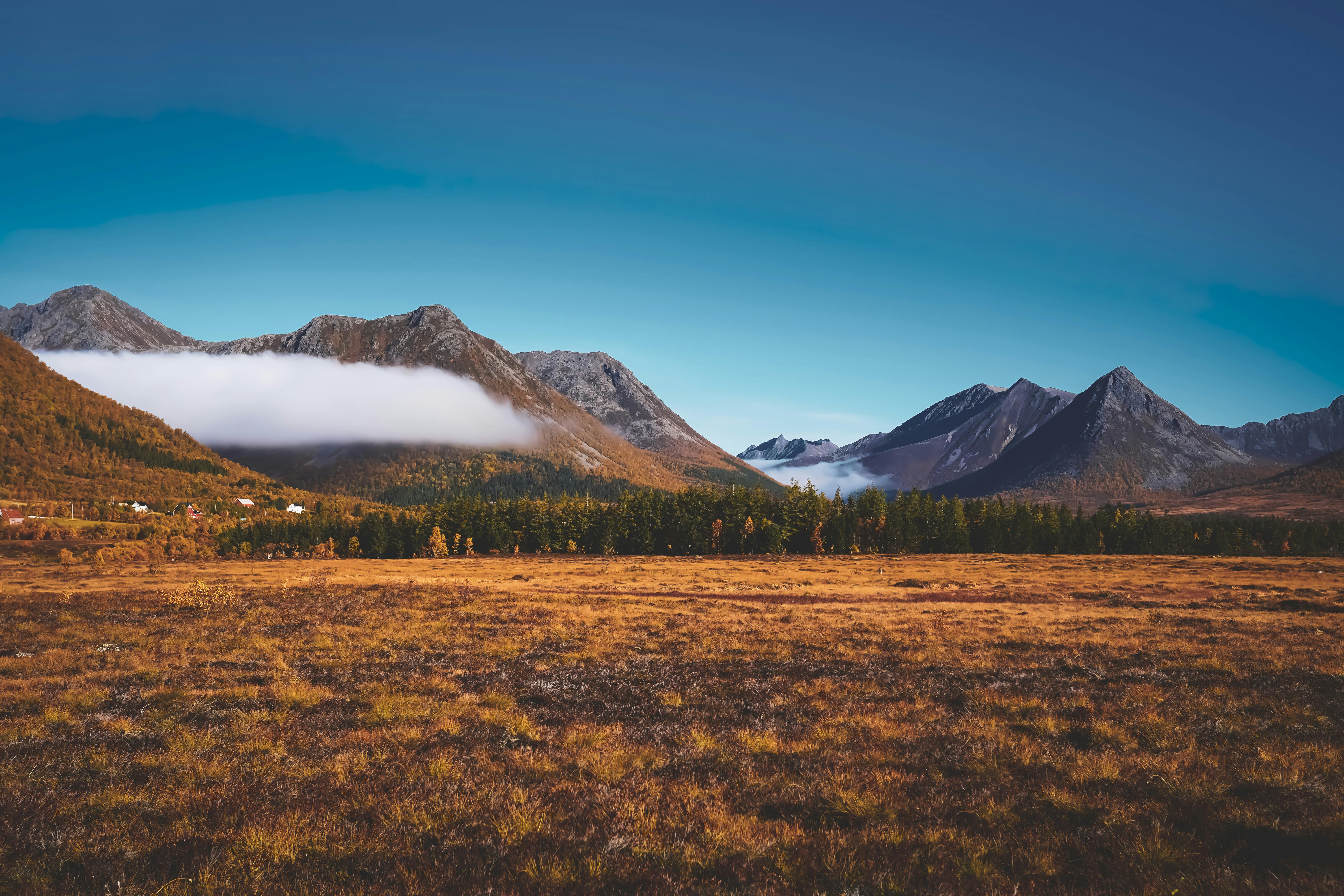 Mountain ridge covered with clouds under blue sky · Free Stock Photo
