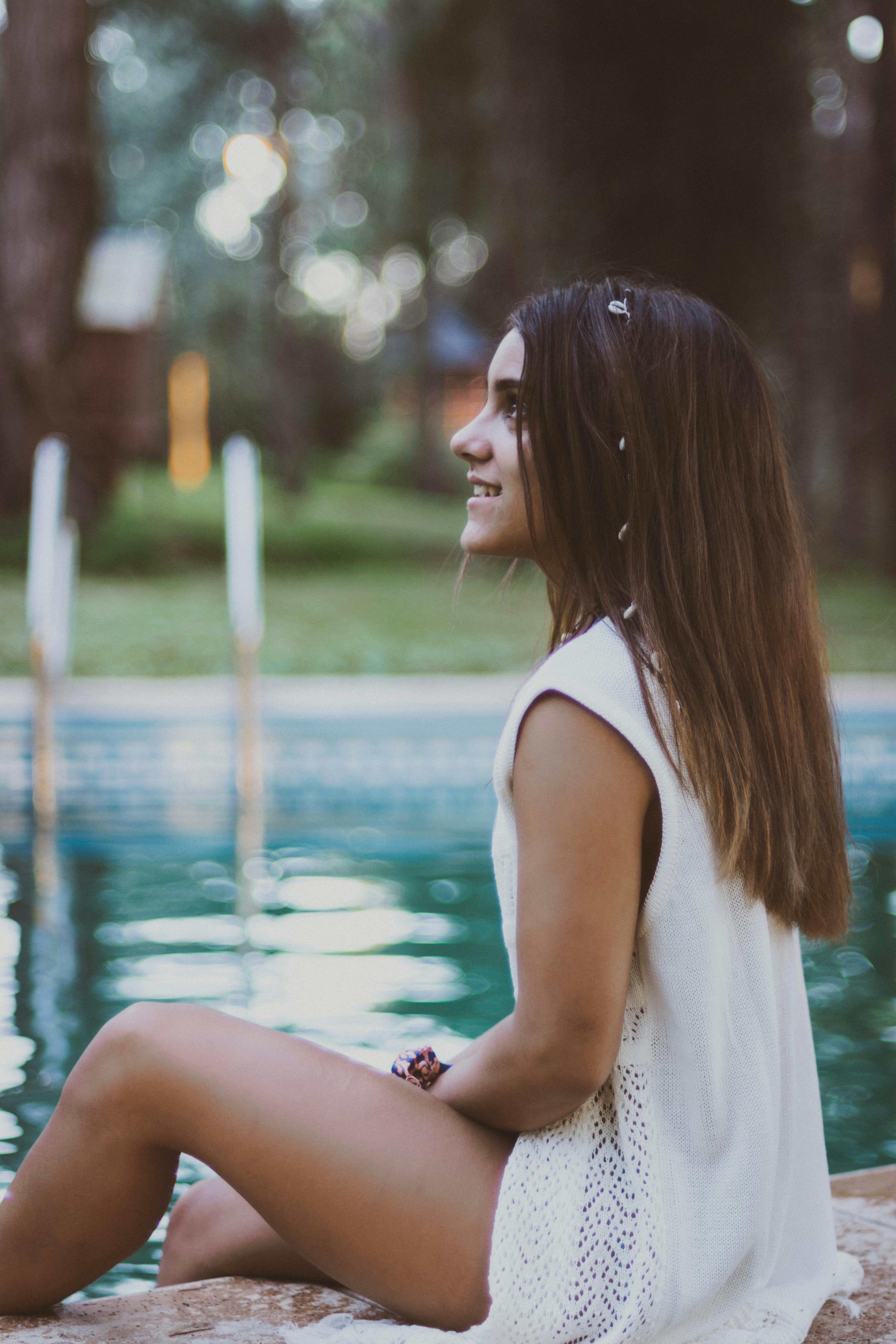 Side View of a Girl Sitting on Poolside · Free Stock Photo