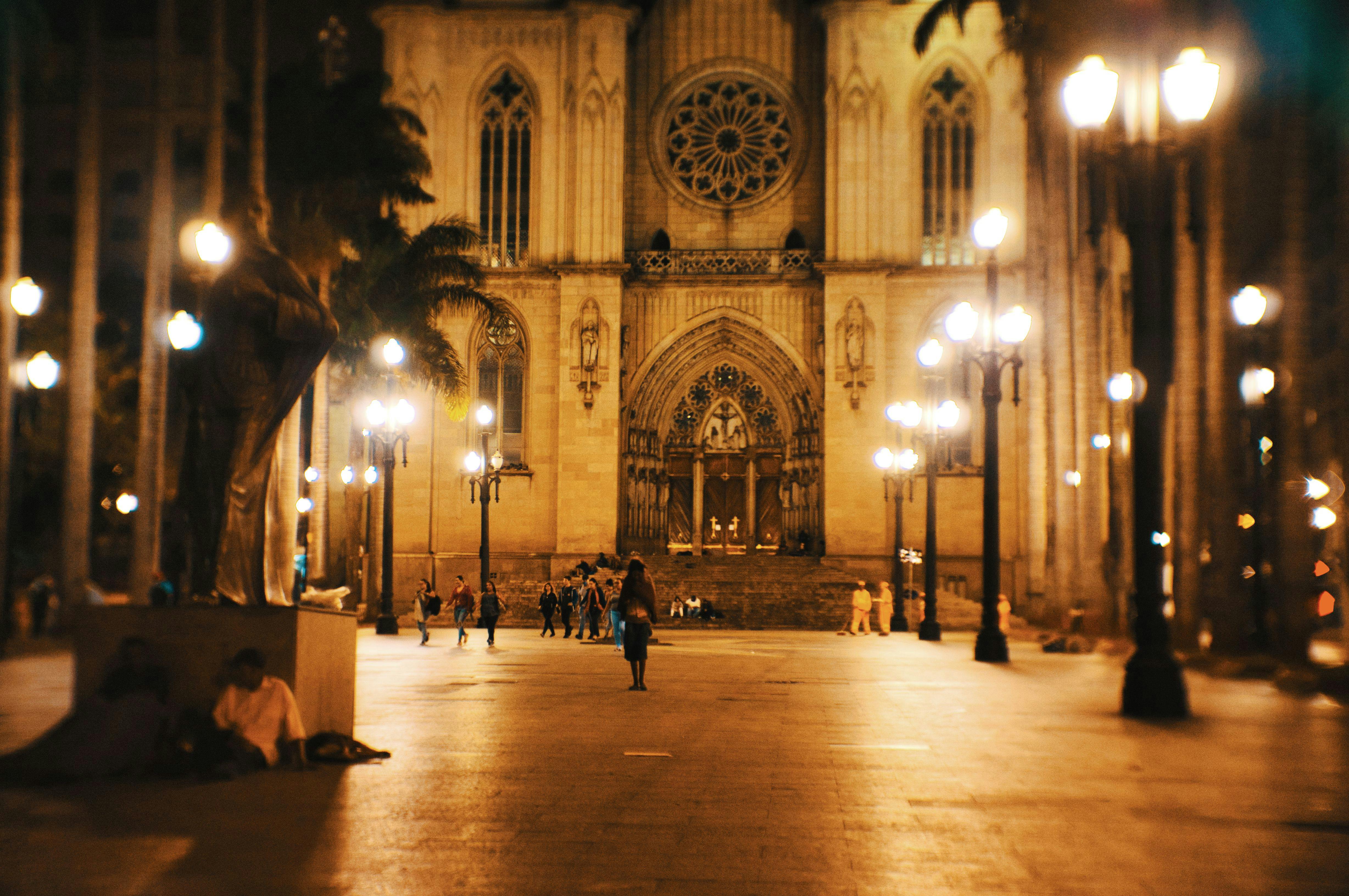 Facade of ancient Catholic church located on square with lanterns and ...