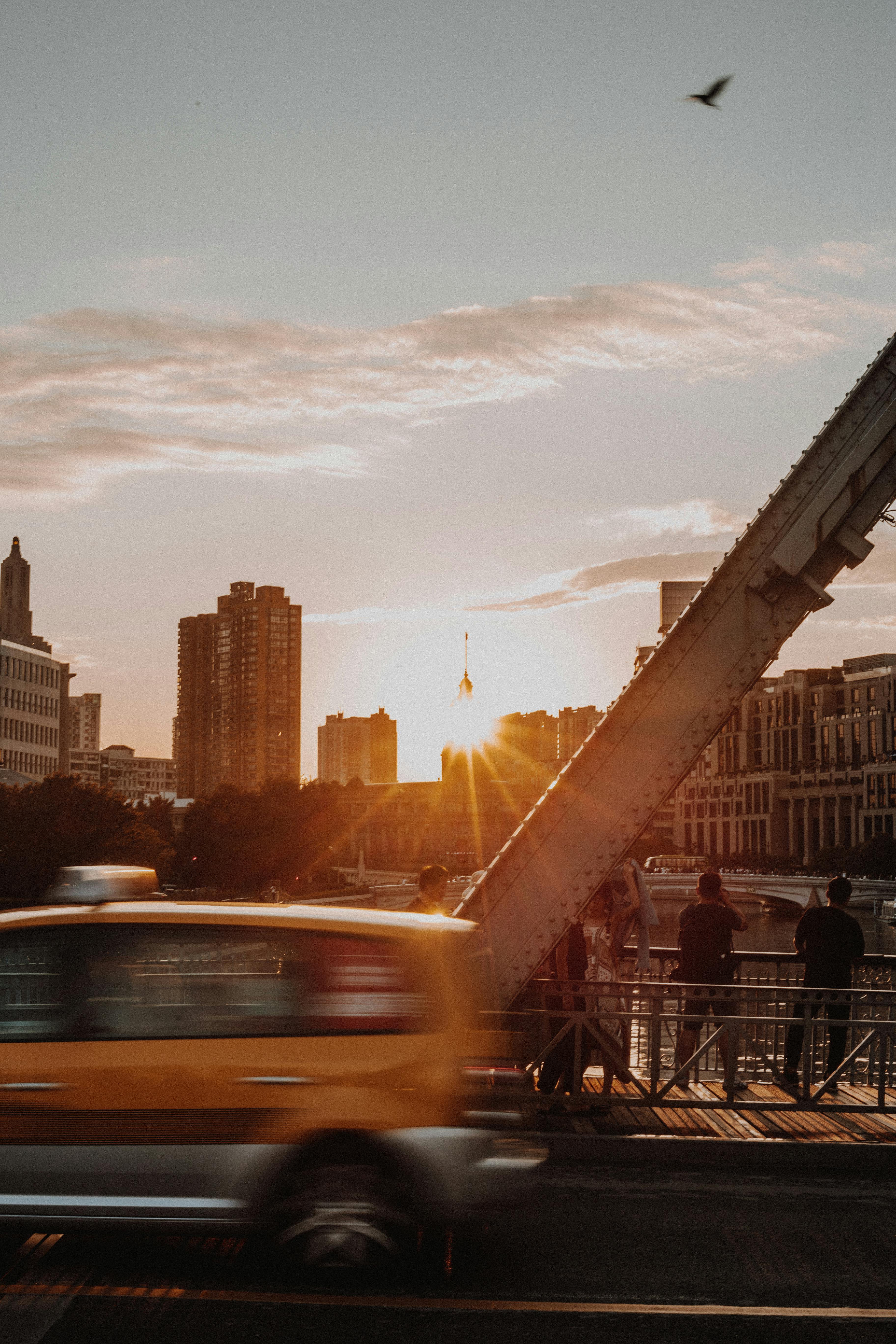 People on Bridge Looking at Sunset over Tall Buildings · Free Stock Photo