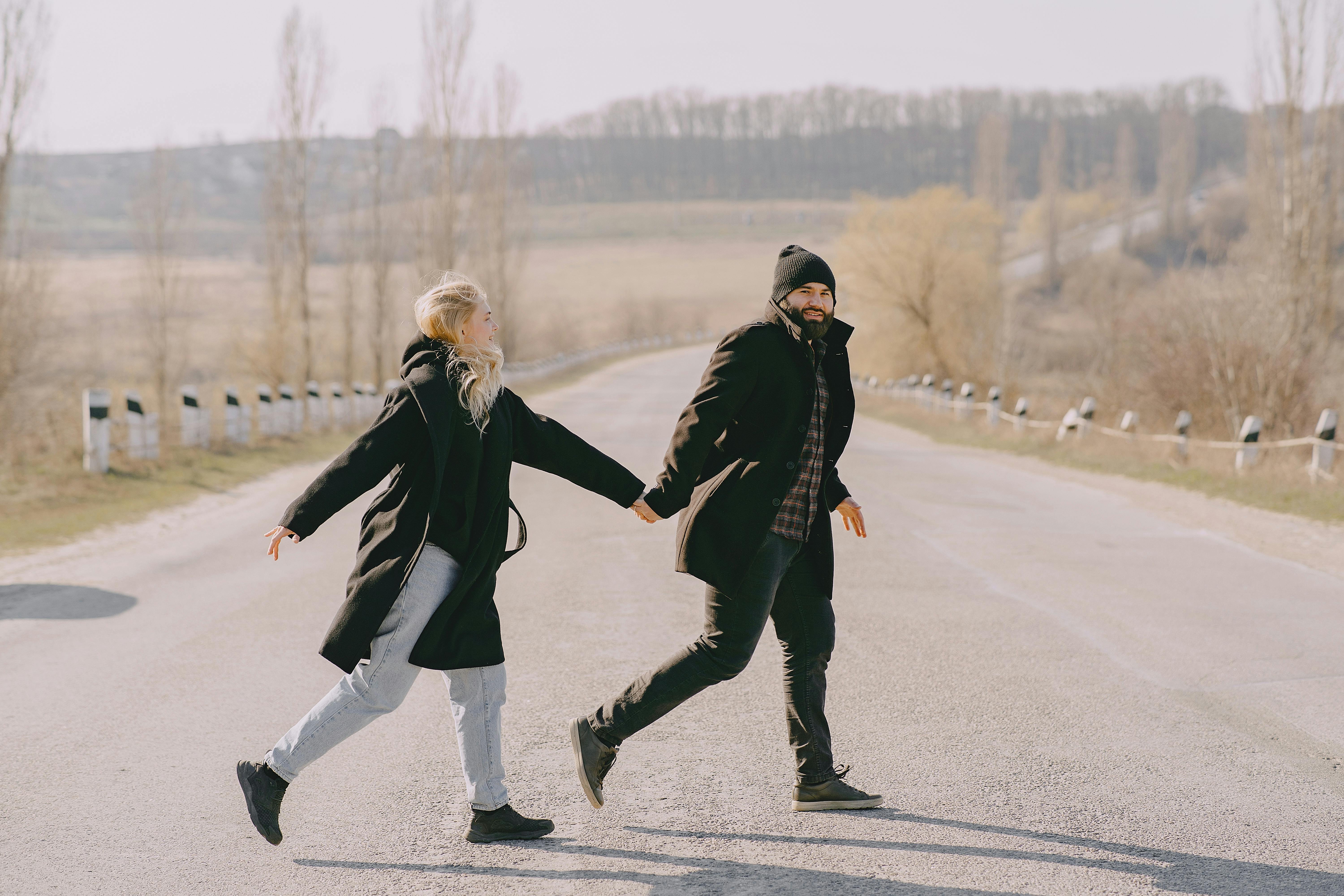 Happy couple crossing road in rural area · Free Stock Photo