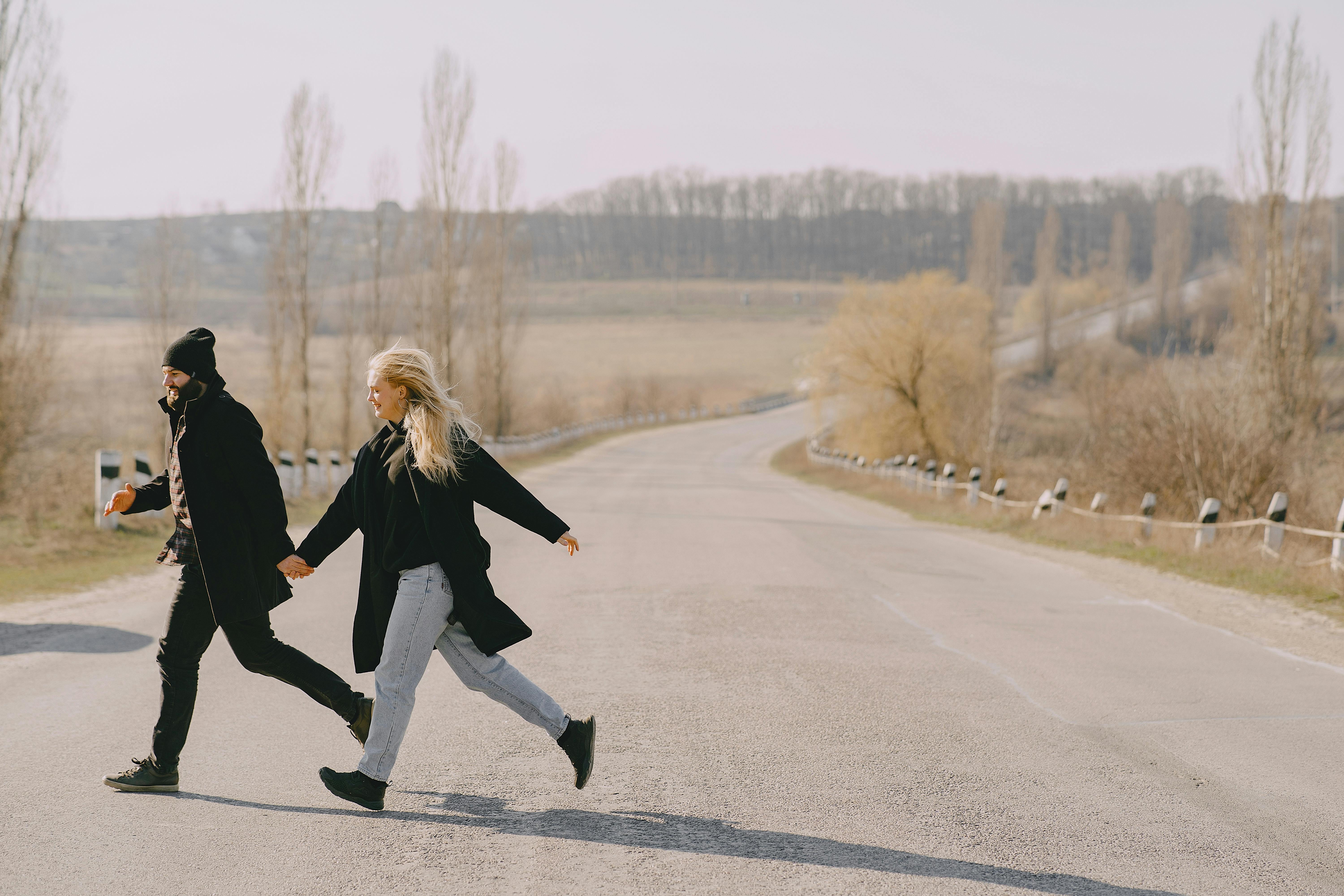 Positive couple running across road in countryside · Free Stock Photo