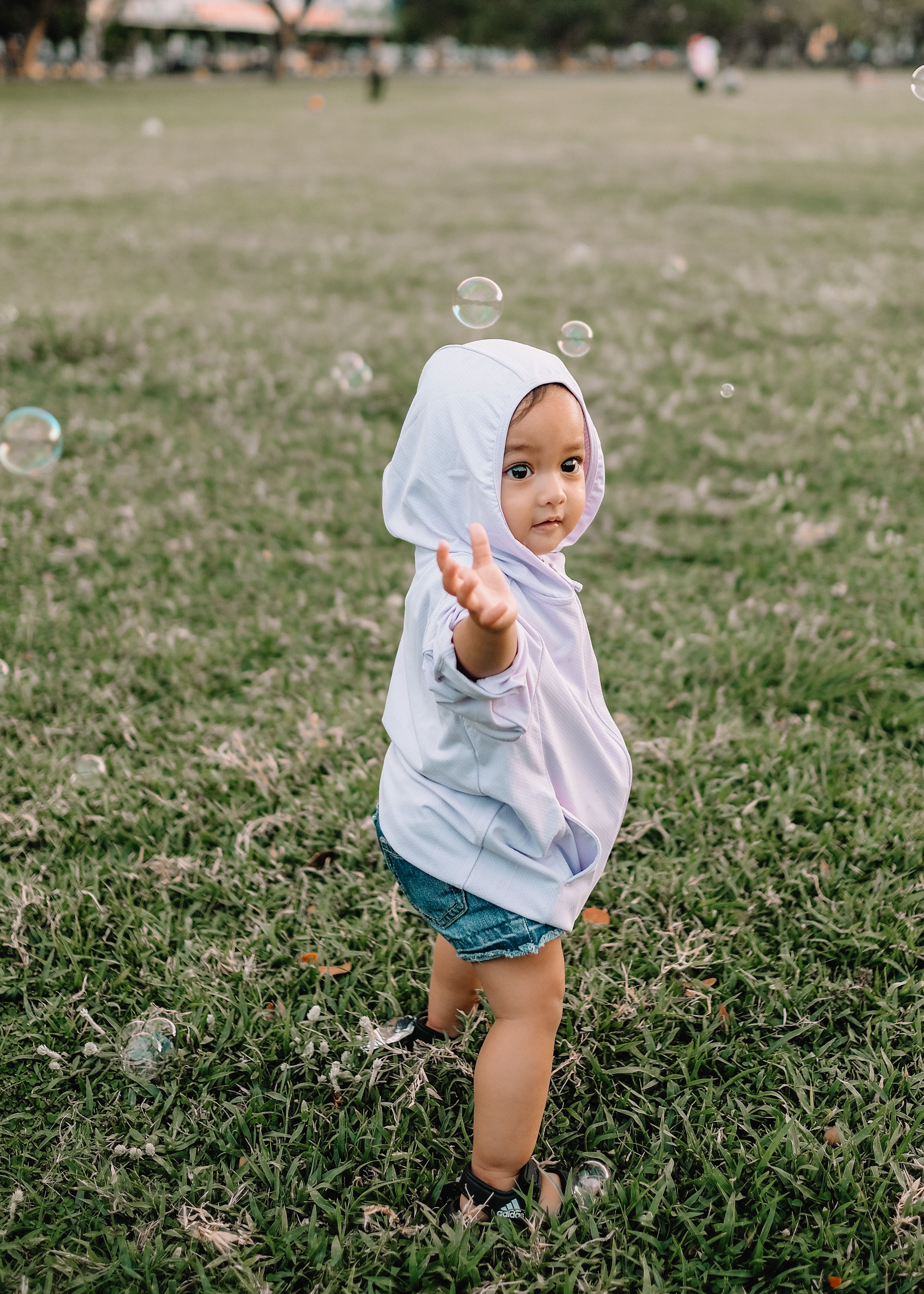 Little child reaching arm in green field under soap bubbles · Free ...