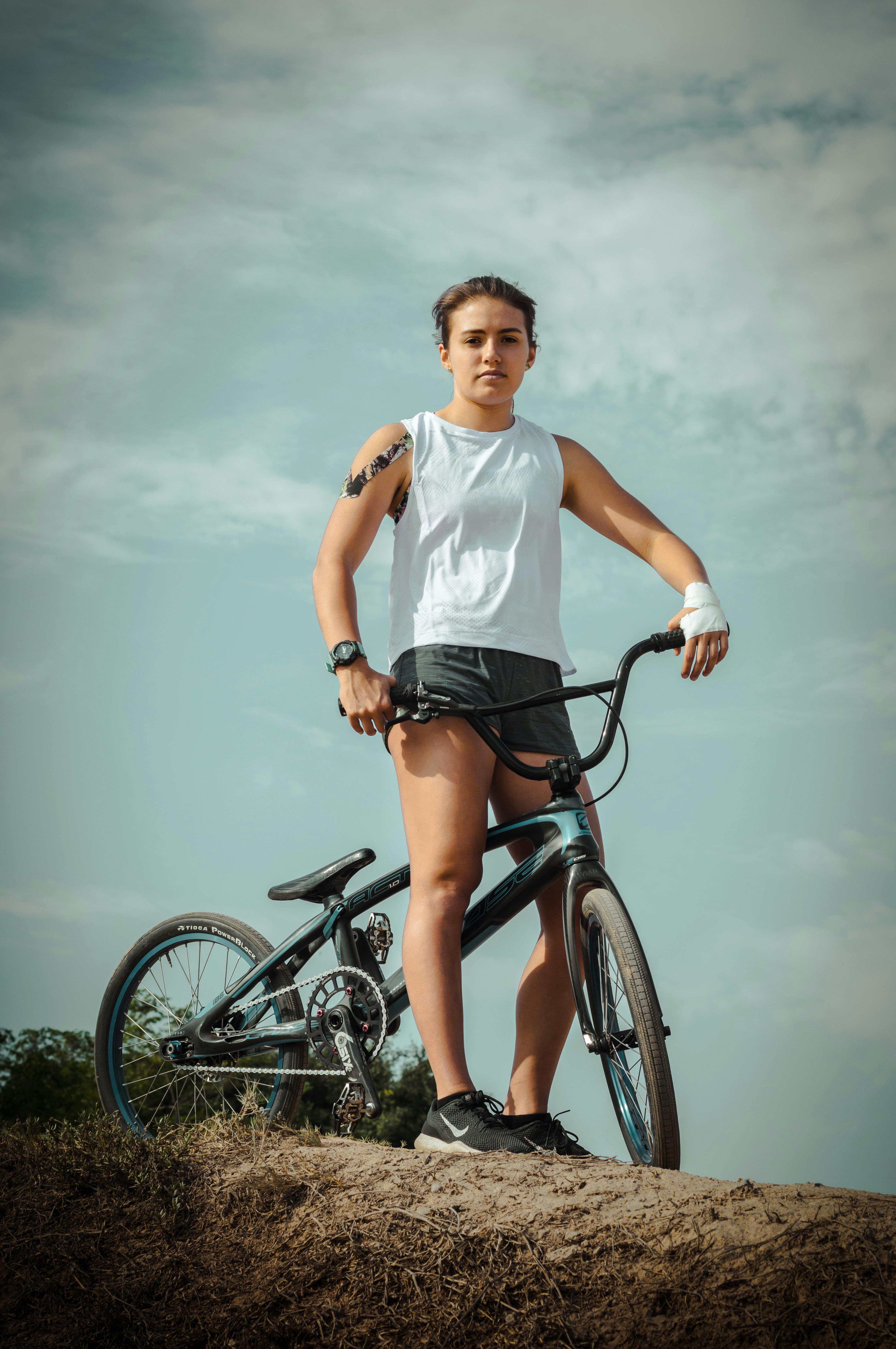 Woman in White Tank Top Riding on Black Bicycle · Free Stock Photo