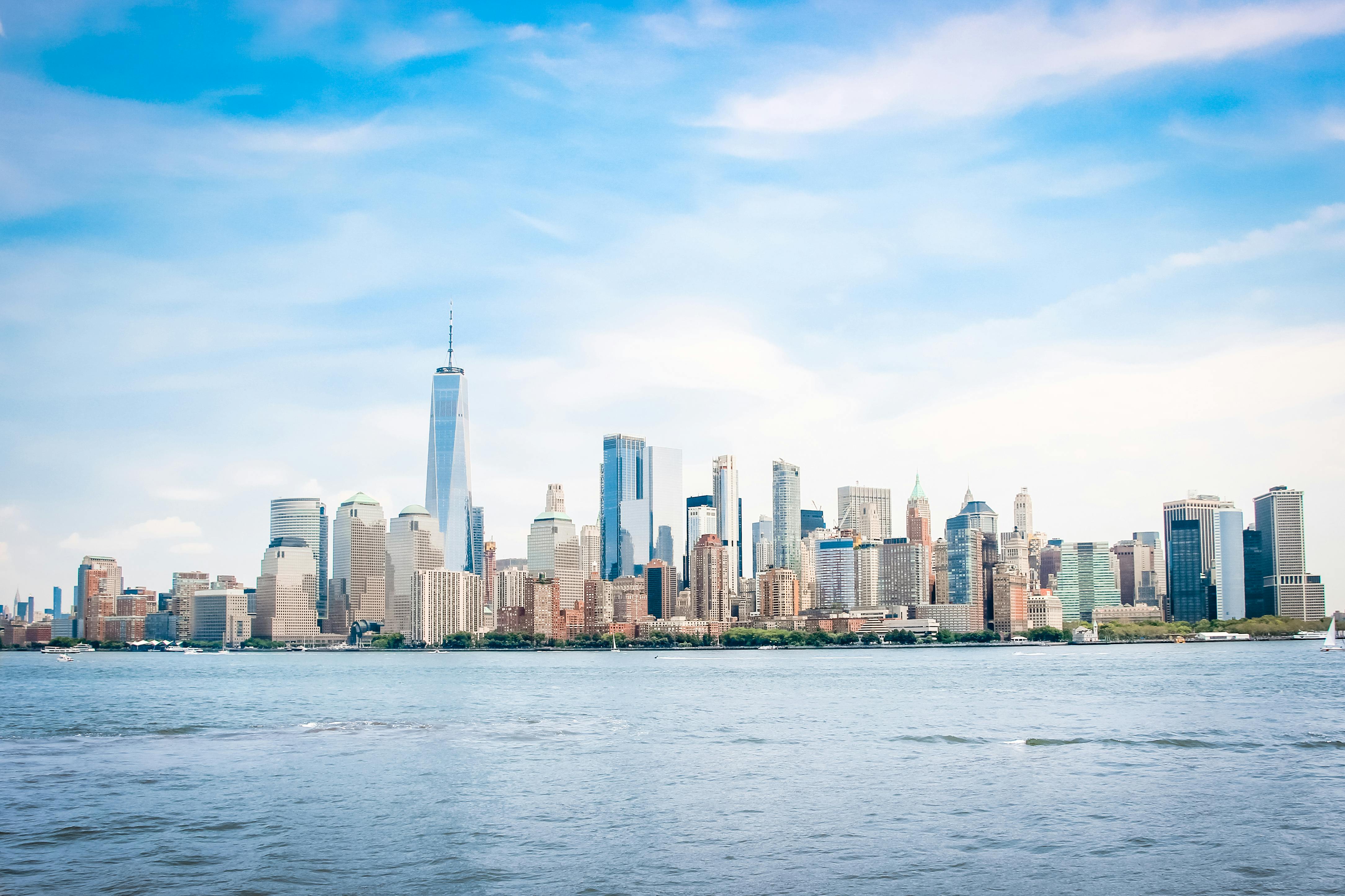 Contemporary skyscrapers near sea under bright cloudy sky · Free Stock ...