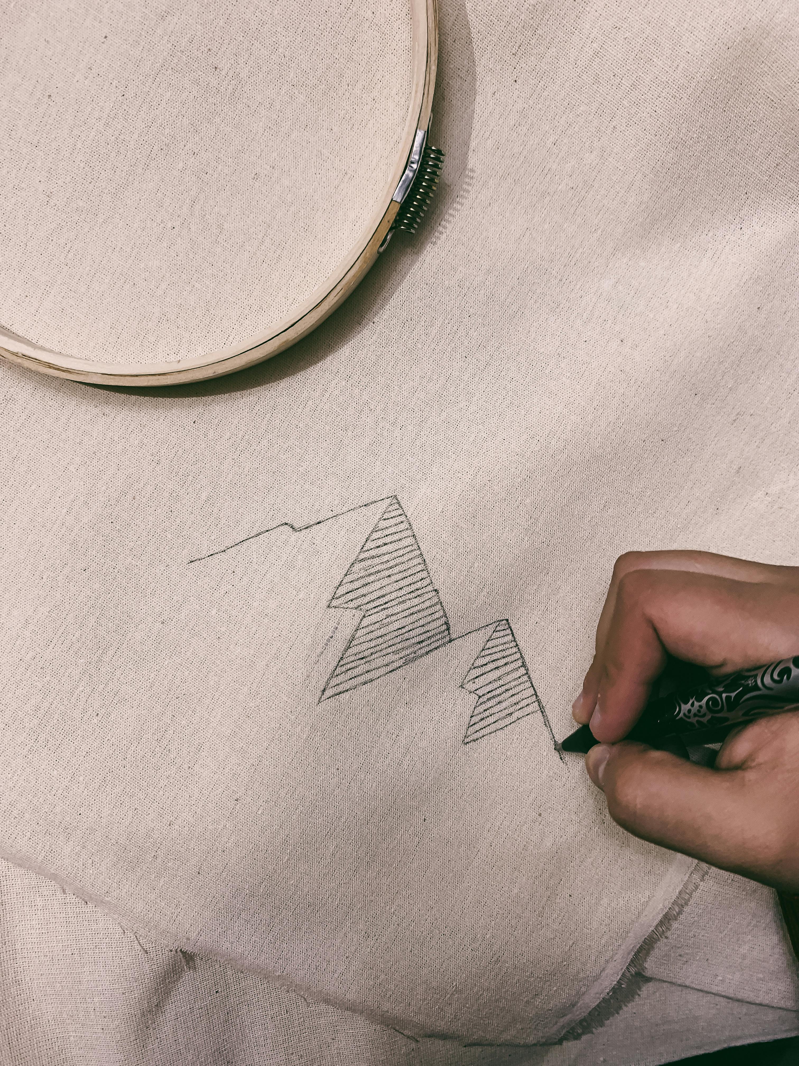 A Person Drawing on a Fabric Using a Pen · Free Stock Photo