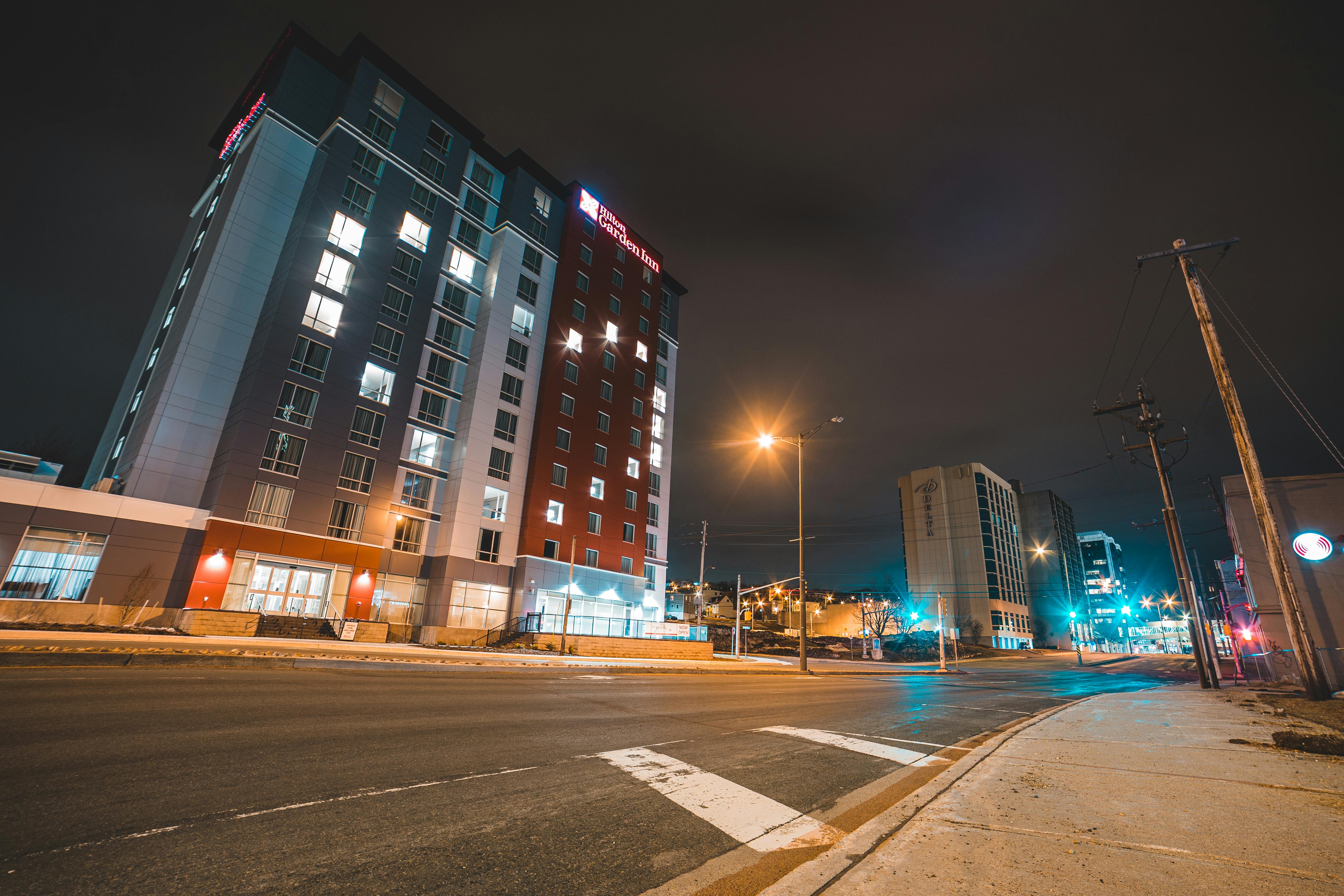 Contemporary building facades near road in city at night · Free Stock Photo