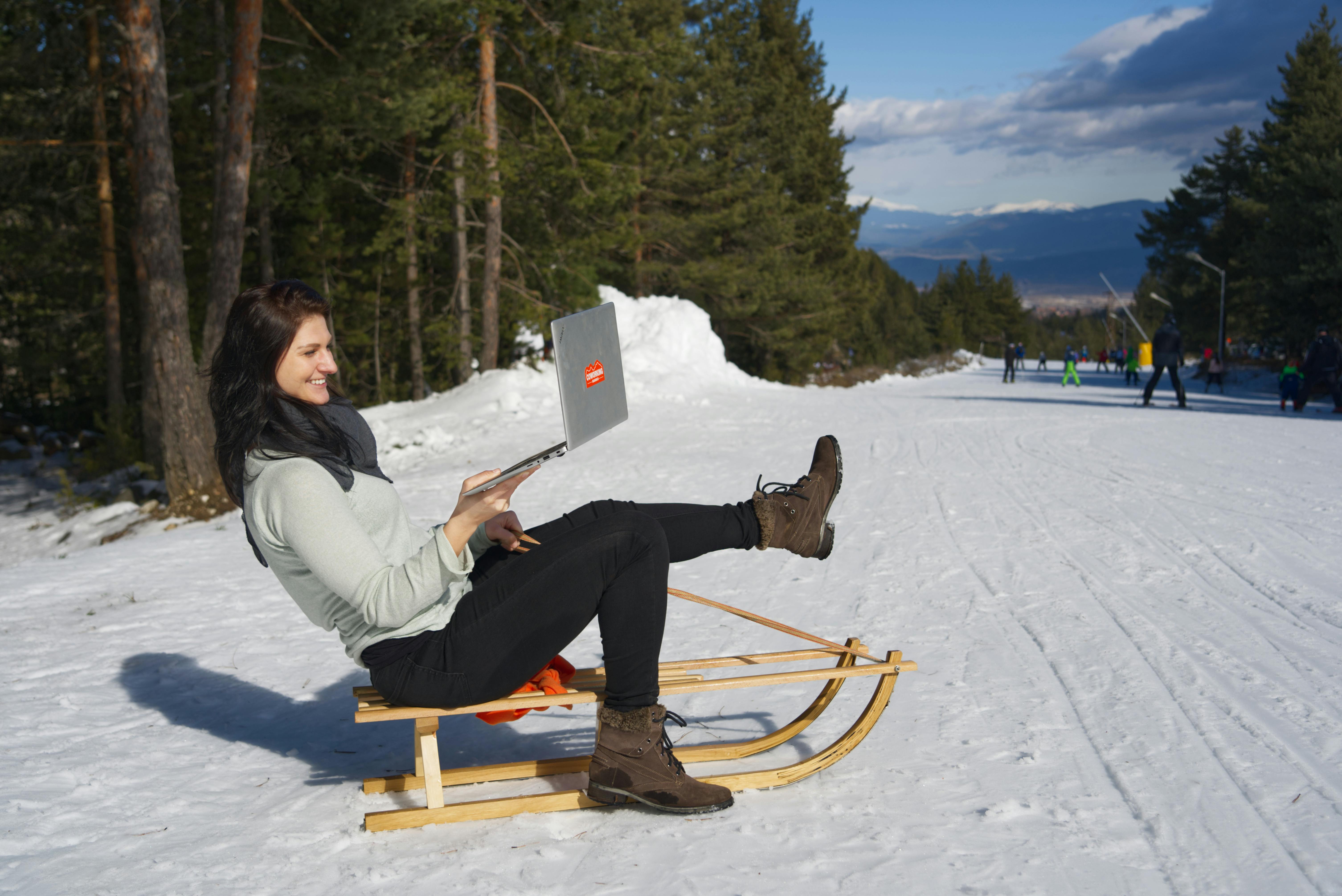 Woman Sitting on Wooden Sled Using Silver Macbook · Free Stock Photo