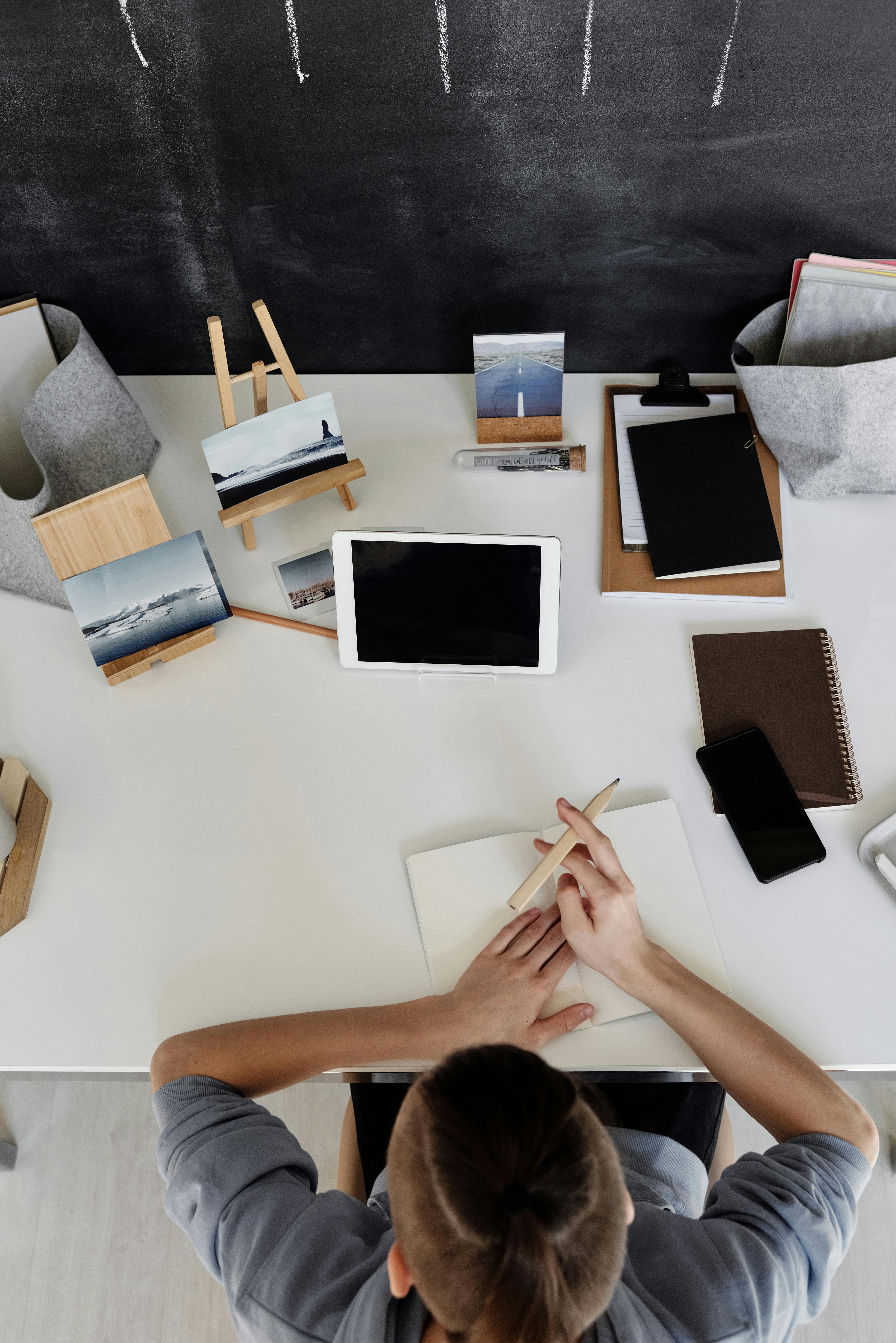 Person with Pencil Sitting at Desk with Notepad and Tablet · Free Stock ...