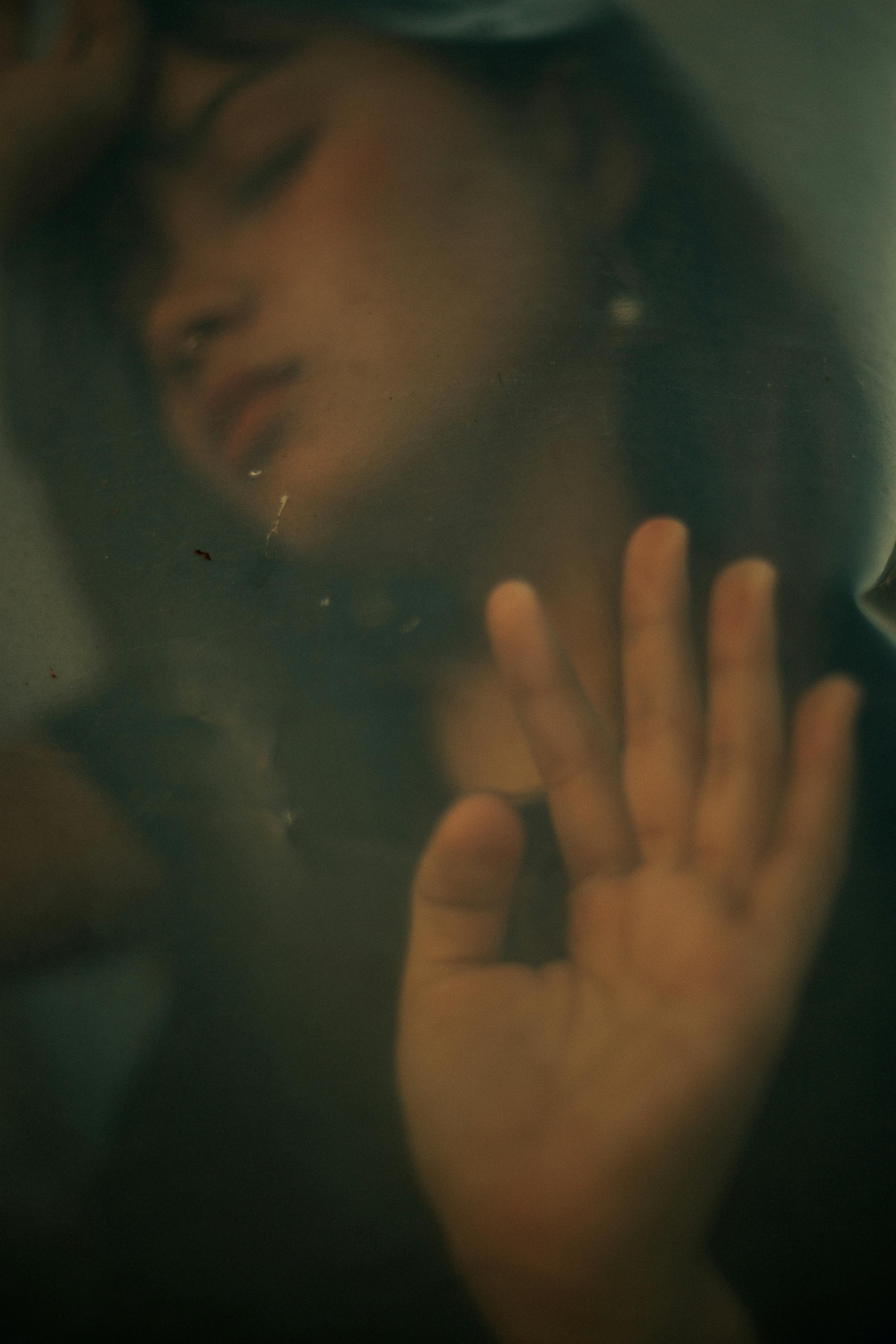 Serene woman putting hand on surface of glass · Free Stock Photo