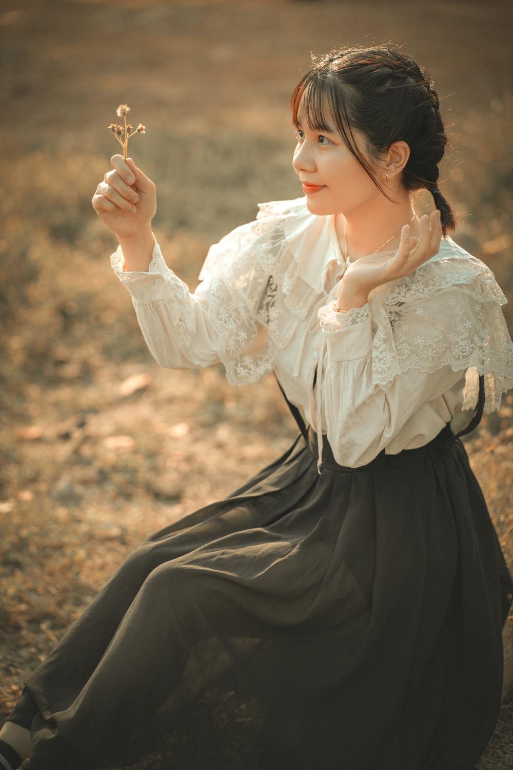 Woman In White Long Sleeve Shirt And Black Skirt Holding Brown Stick