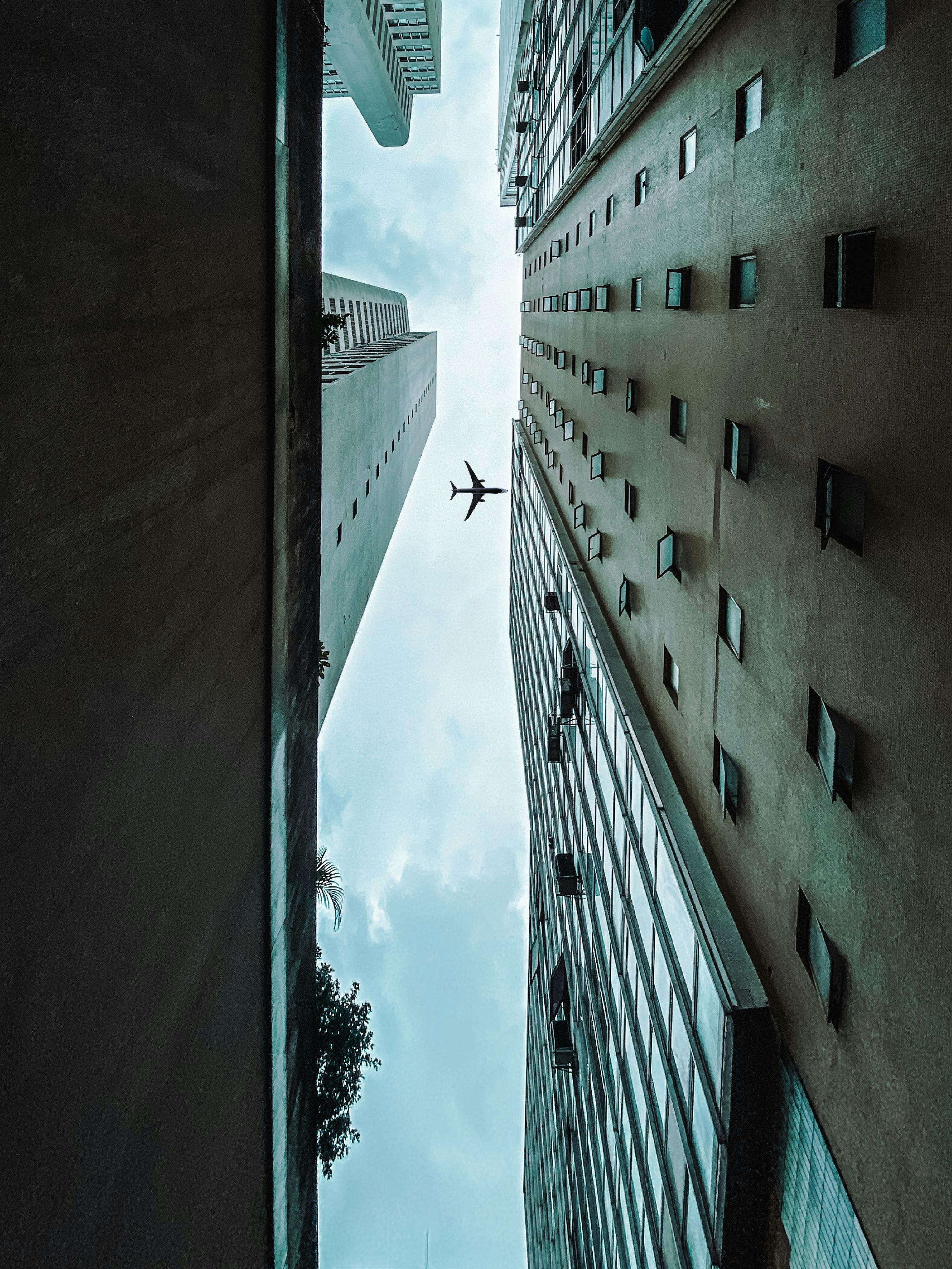 Low Angle of Airplane Flying Over Buildings · Free Stock Photo