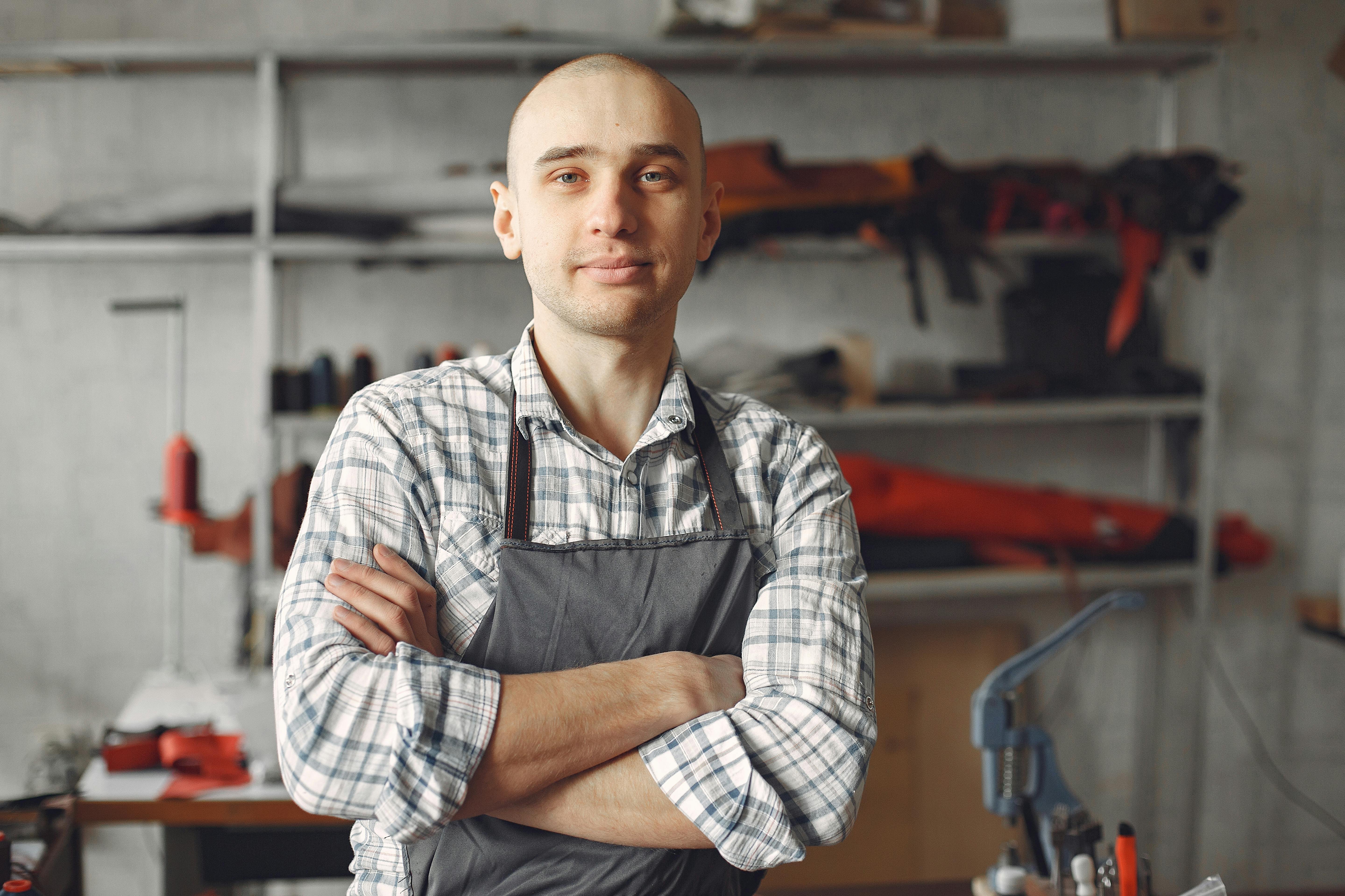 Cheerful young tanner man in apron in workshop · Free Stock Photo