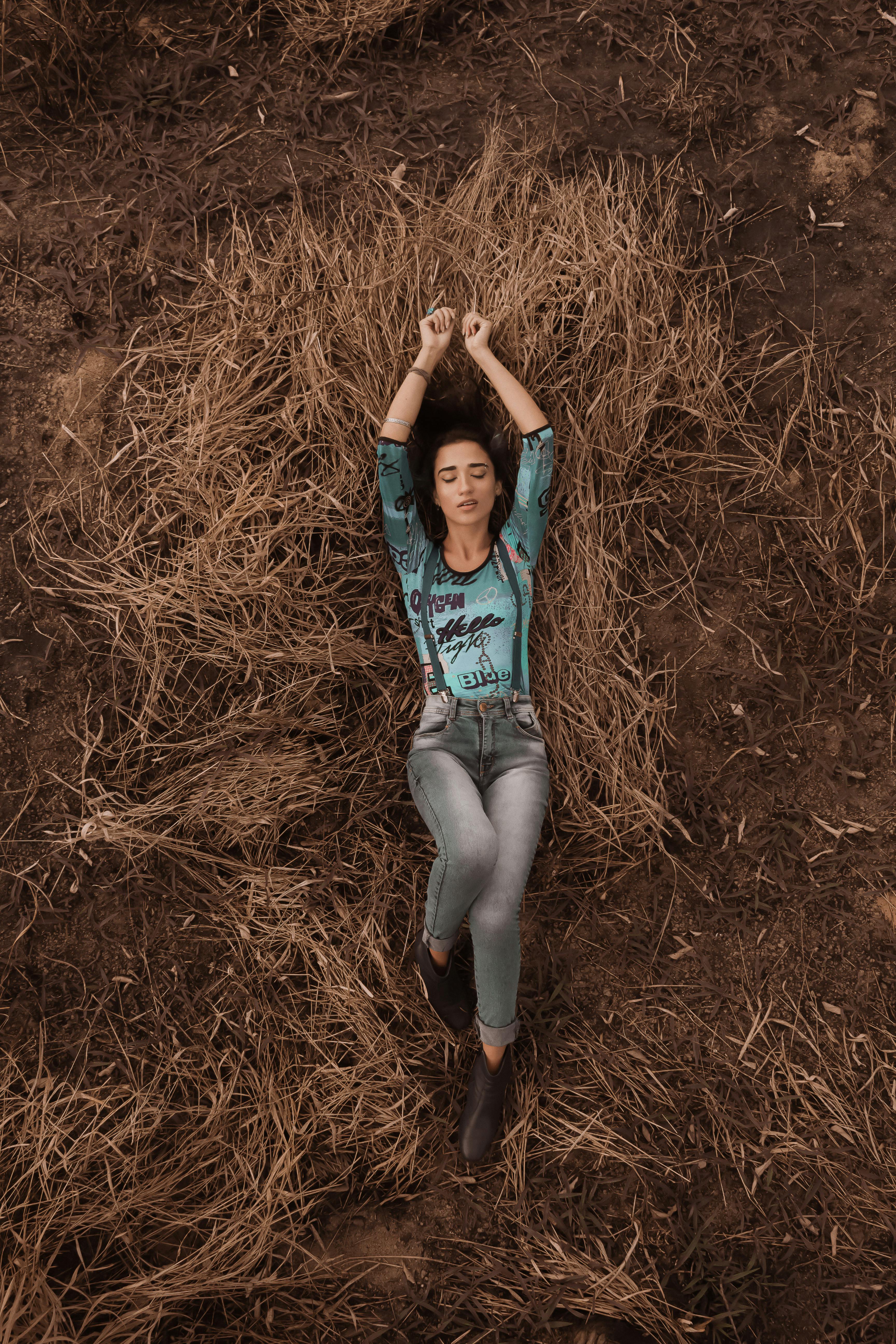 Relaxed woman lying on pile of hay in countryside · Free Stock Photo