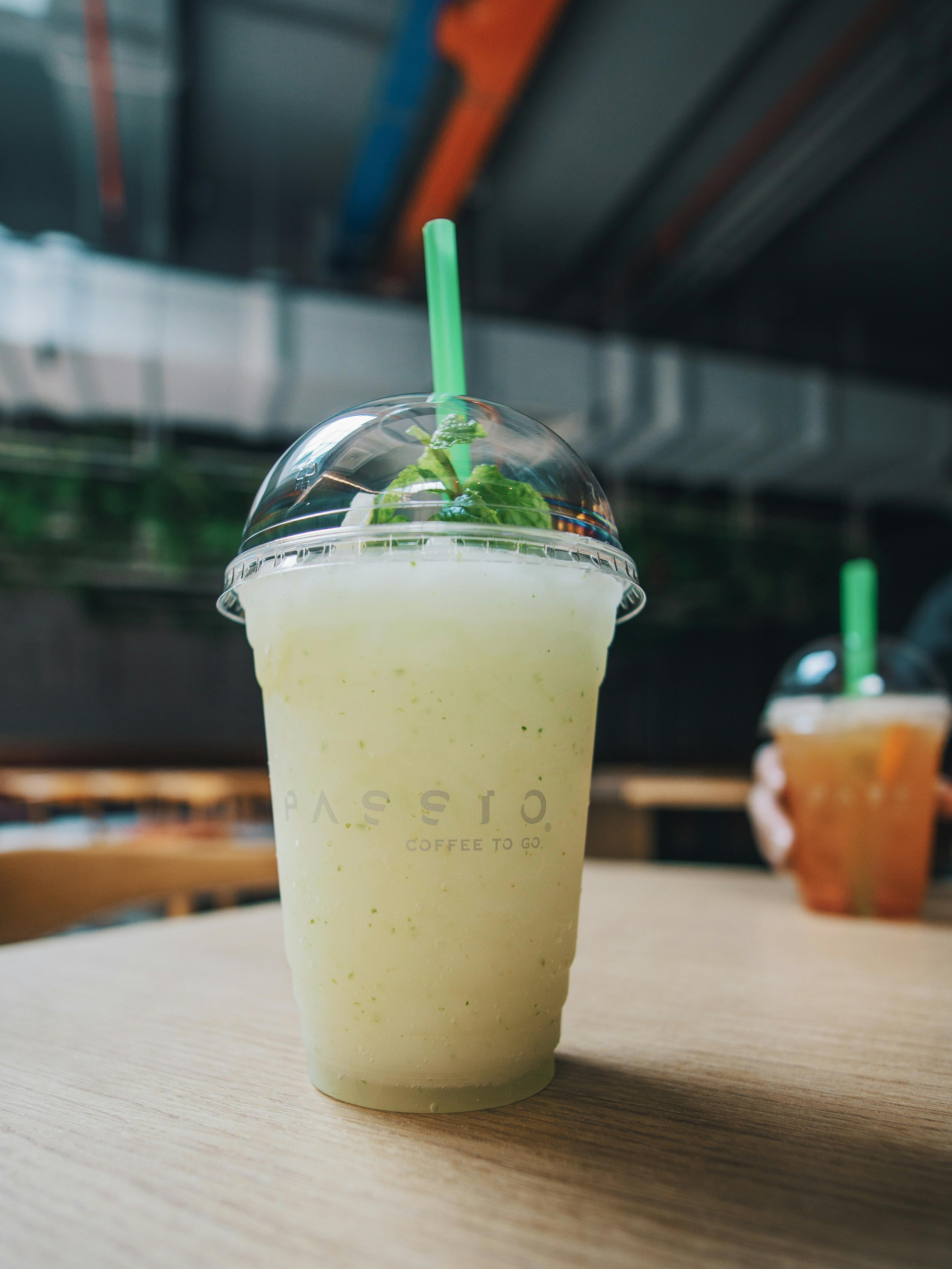 Cup of delicious cold drink with mint placed on table in cafeteria ...