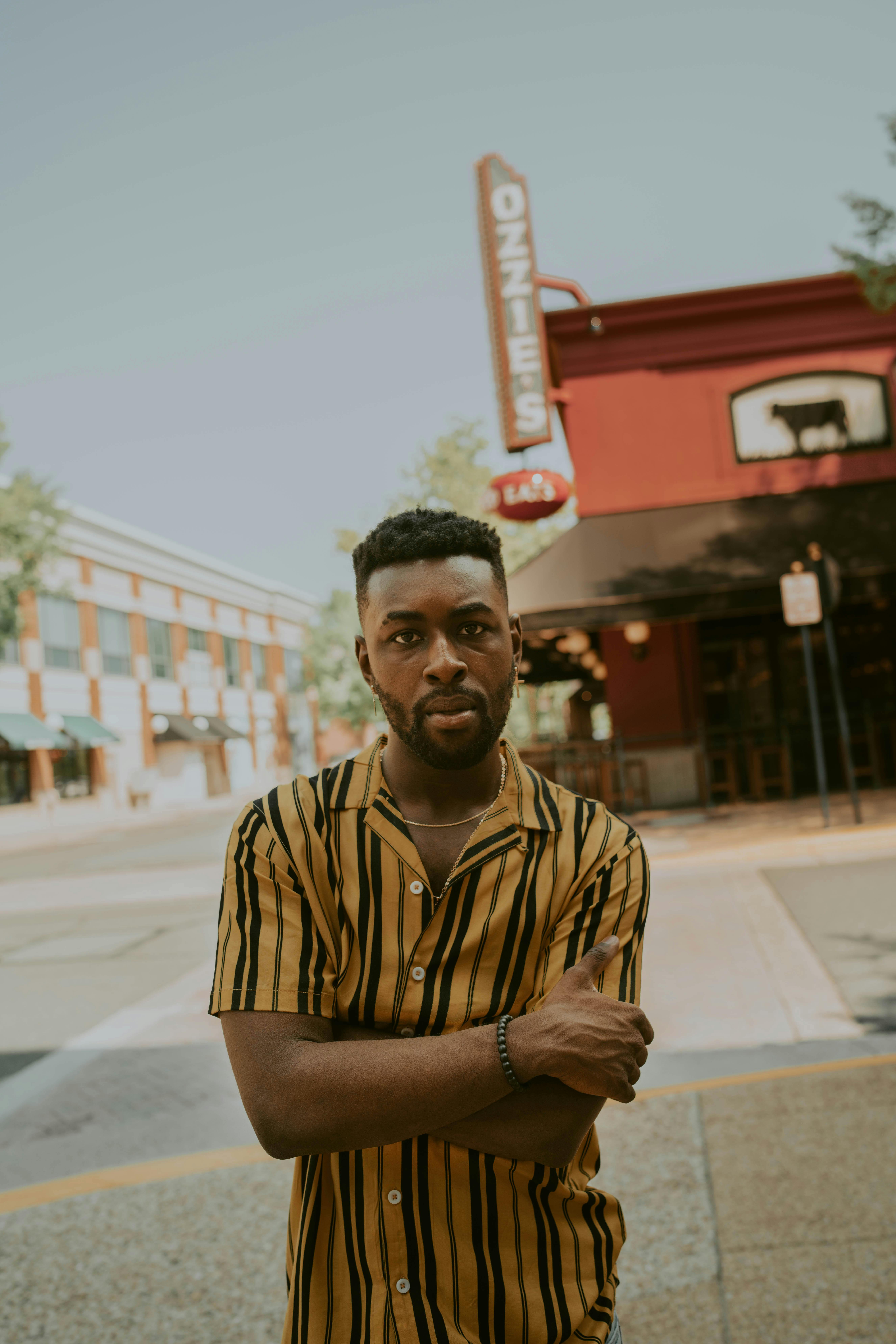 Trendy black man with folded arms on city street · Free Stock Photo