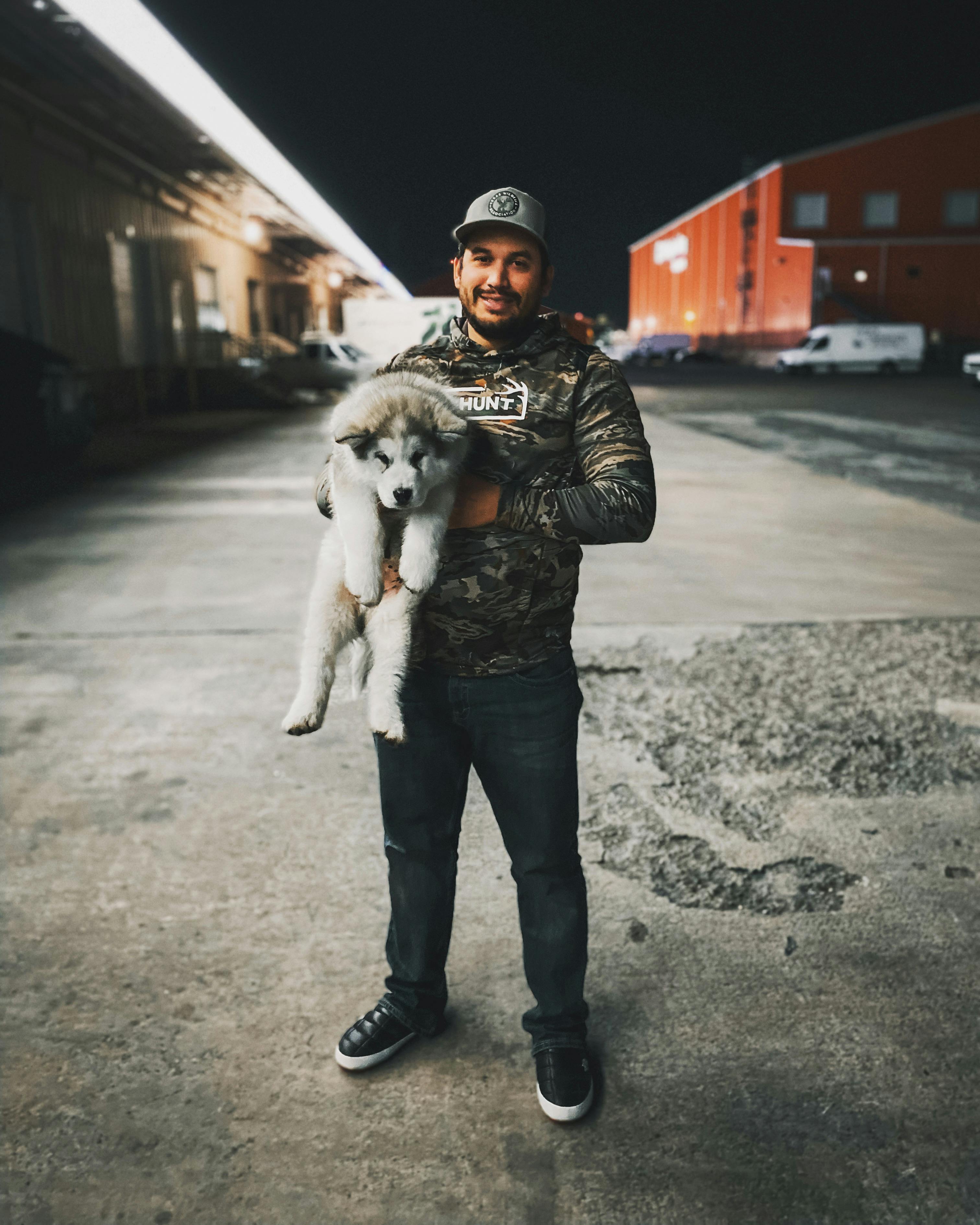 Photo of Man Standing While Carrying His Dog · Free Stock Photo