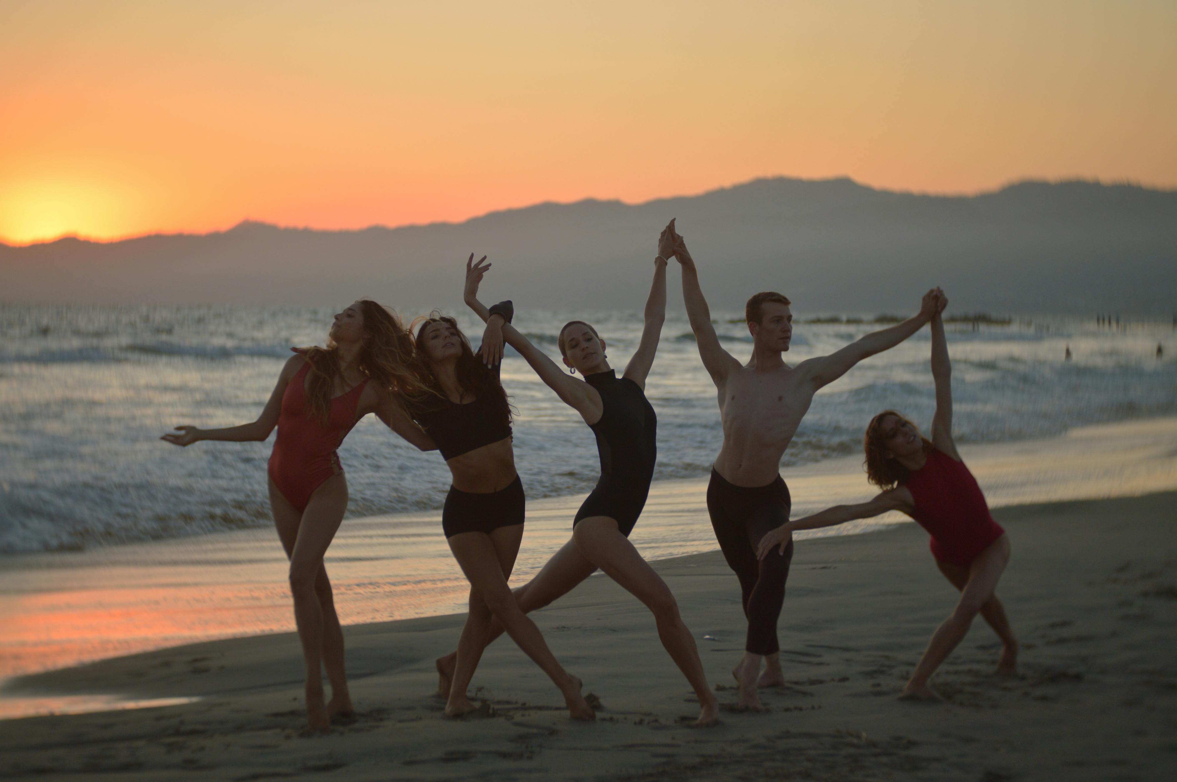 Joyful slim friends dancing on sandy seashore at sundown · Free Stock Photo