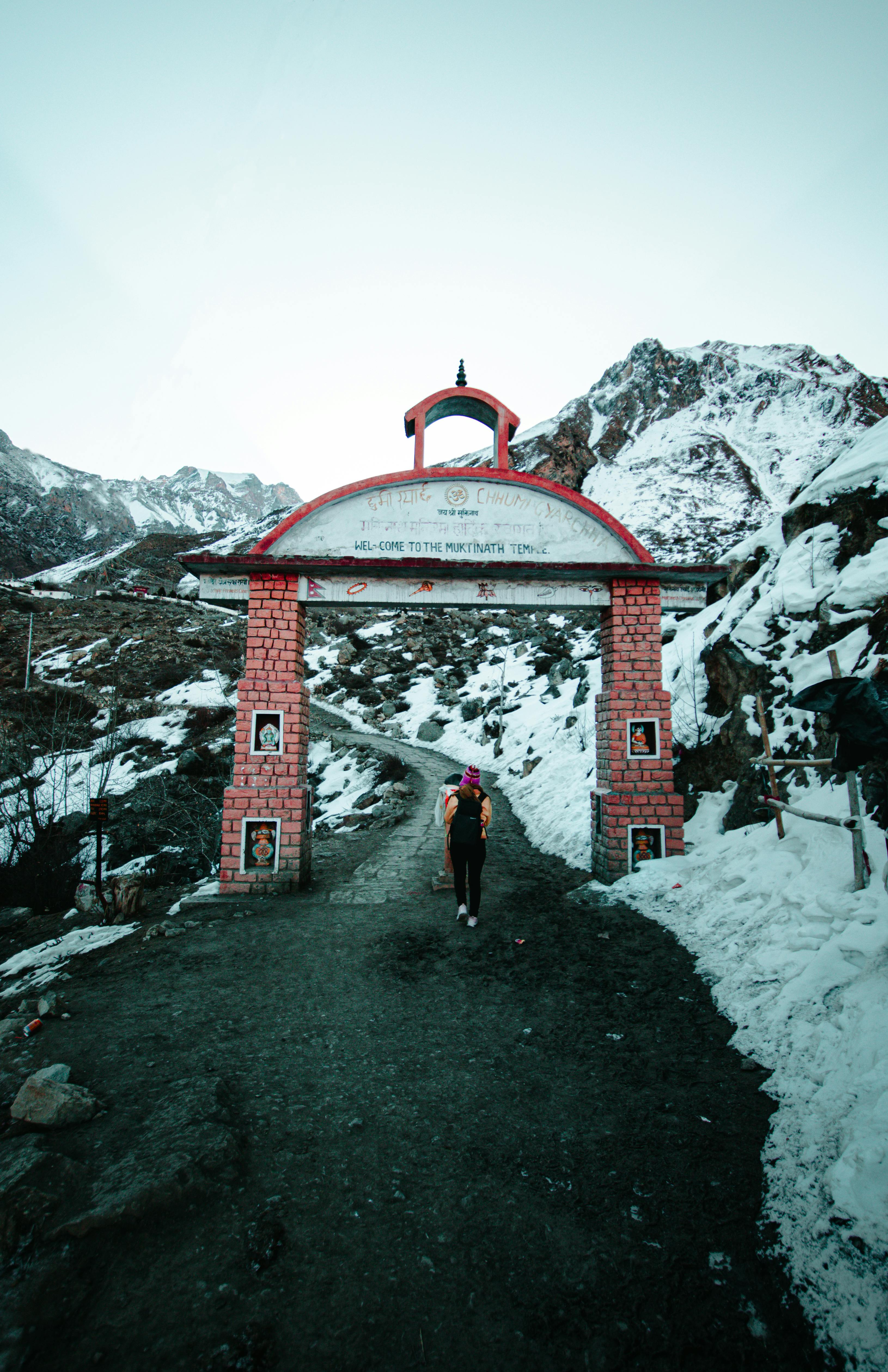 Unrecognizable woman walking through brick gate in mountainous terrain ...