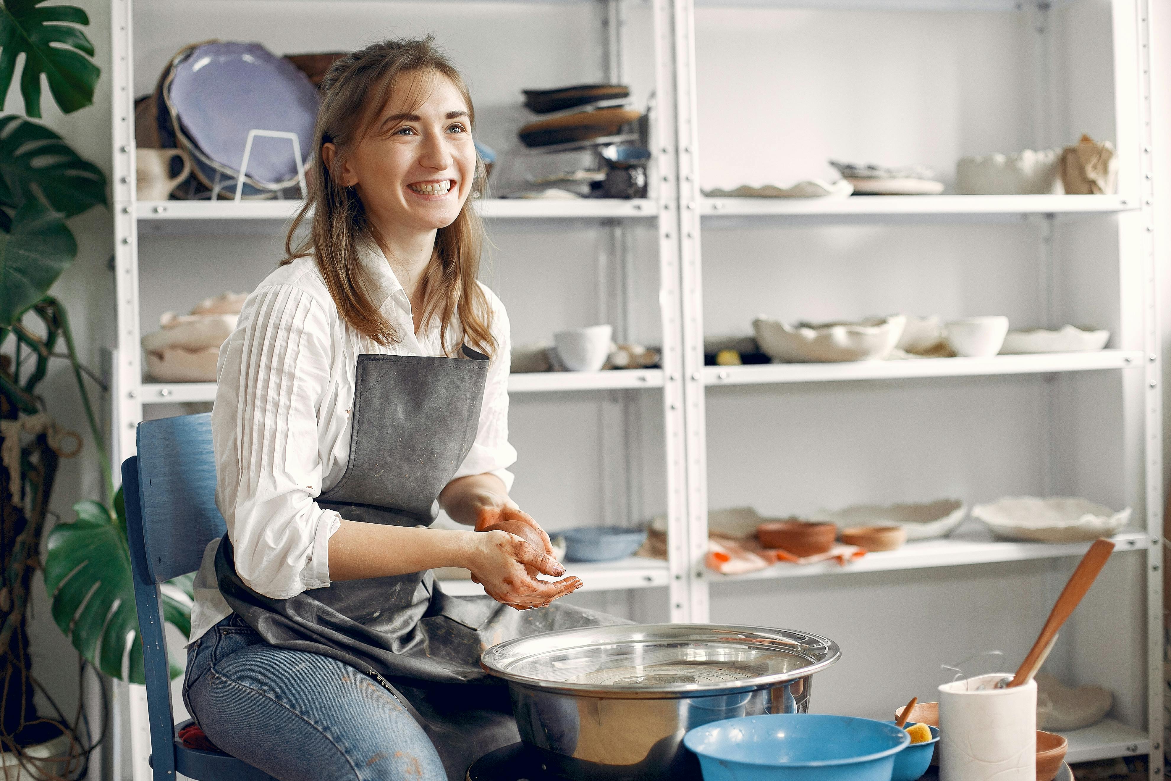 Happy craftswoman with ceramic bowls in pottery · Free Stock Photo