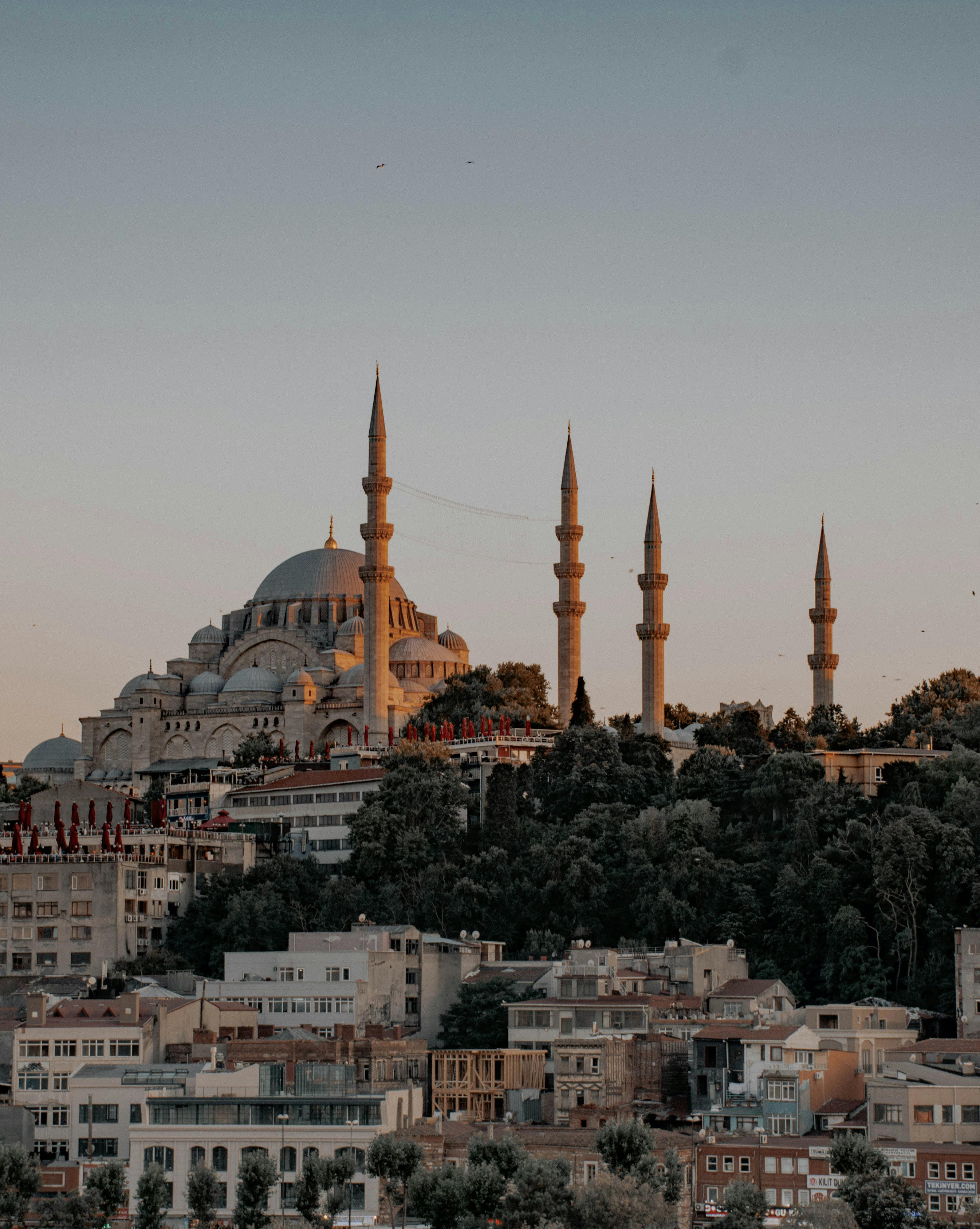 Old mosque on hill and residential buildings in city during sundown ...