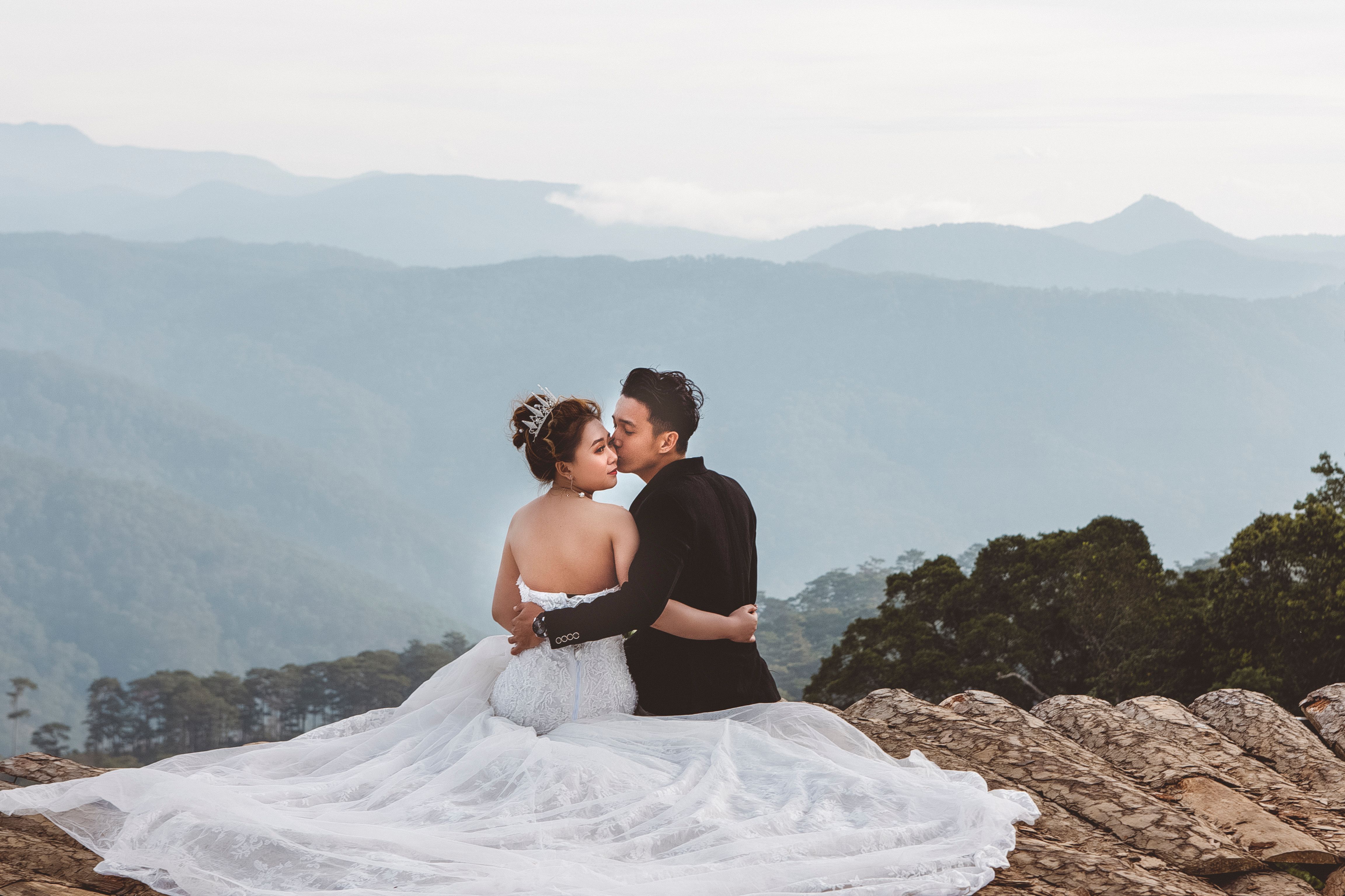 Newlywed Couple Kissing while Sitting on the Edge of a Cliff · Free ...