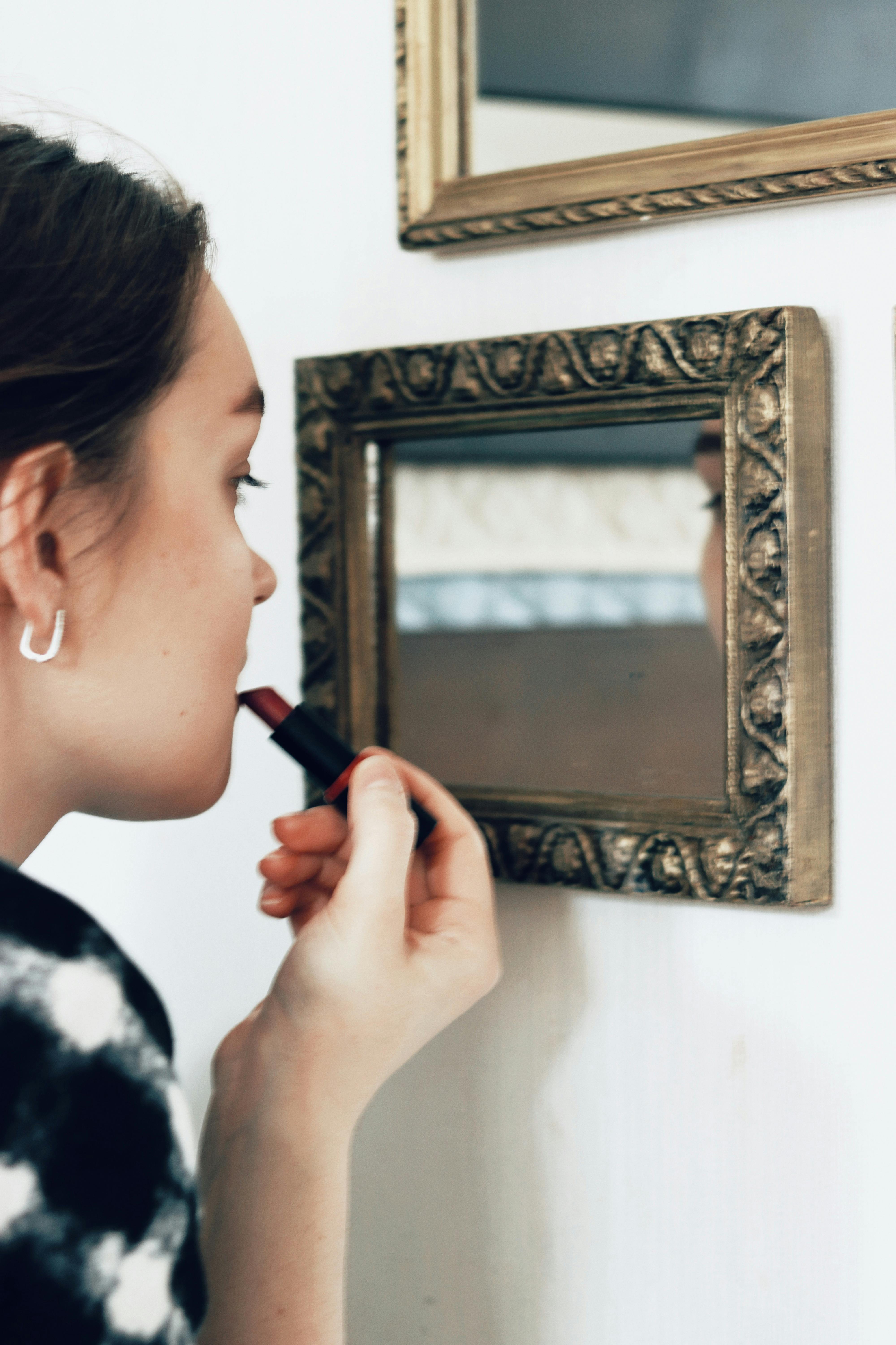 Woman reflecting in mirror while applying makeup · Free Stock Photo