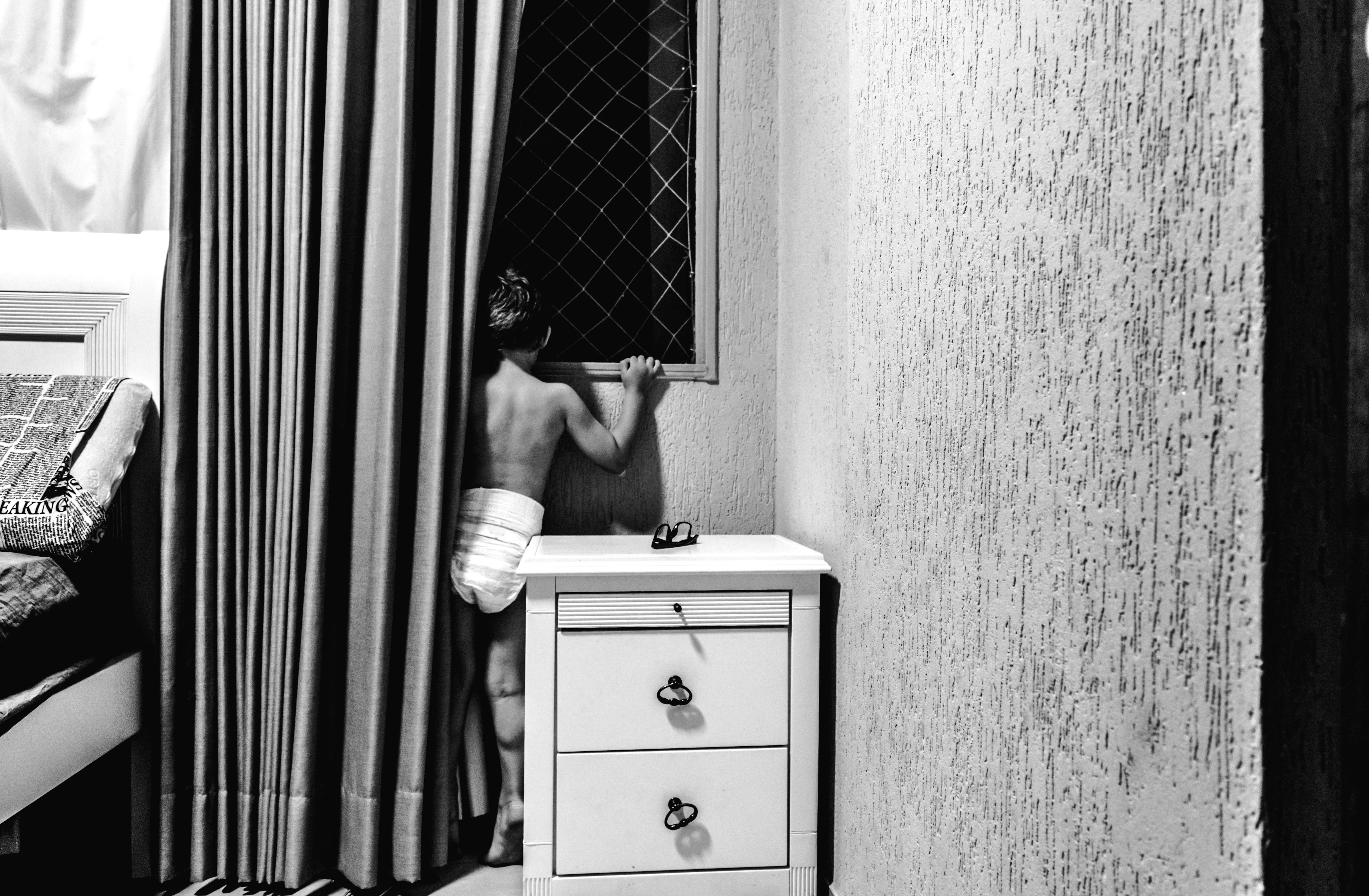 Boy standing in bedroom near window · Free Stock Photo