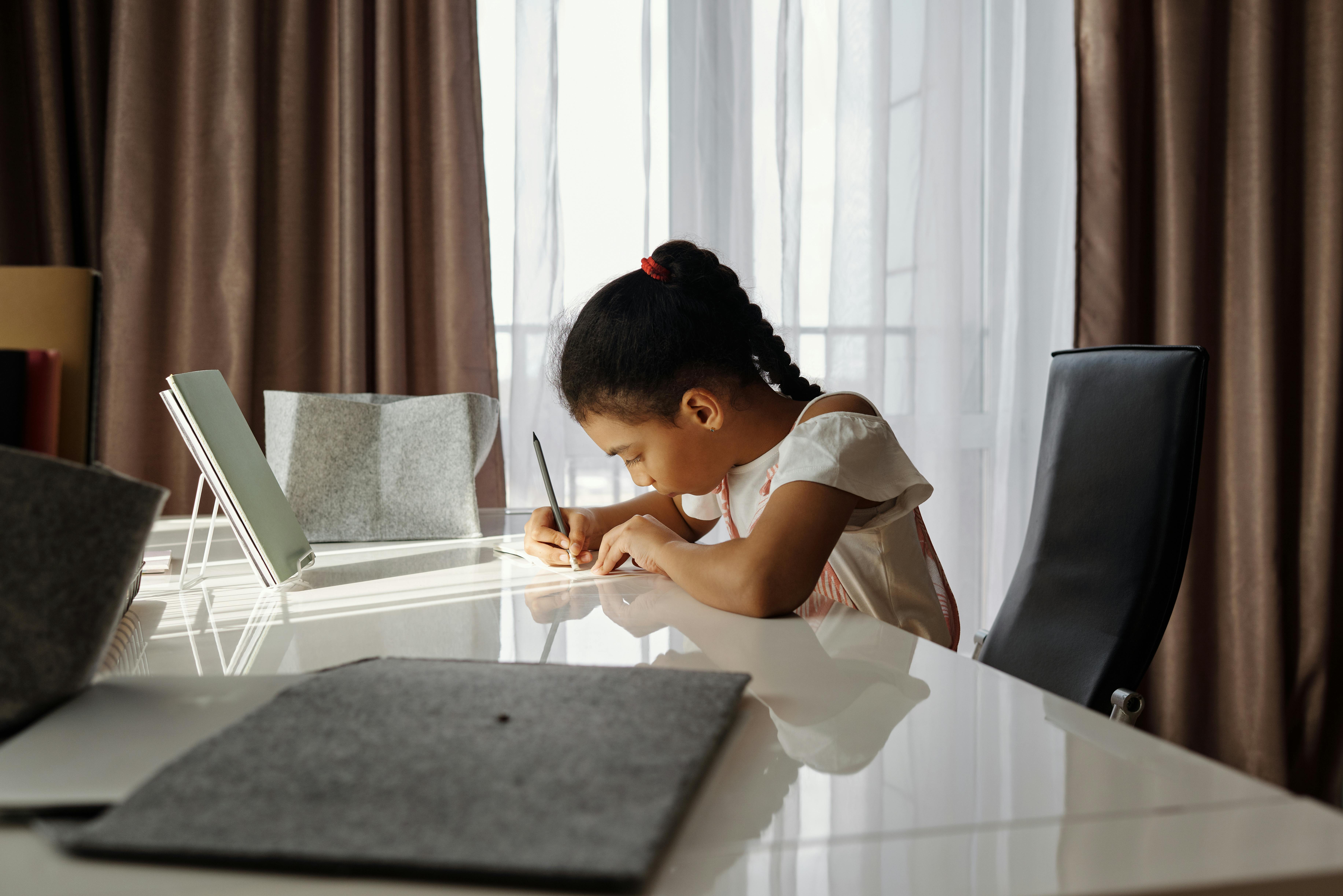 Little Girl Sitting at a Desk and Writing · Free Stock Photo